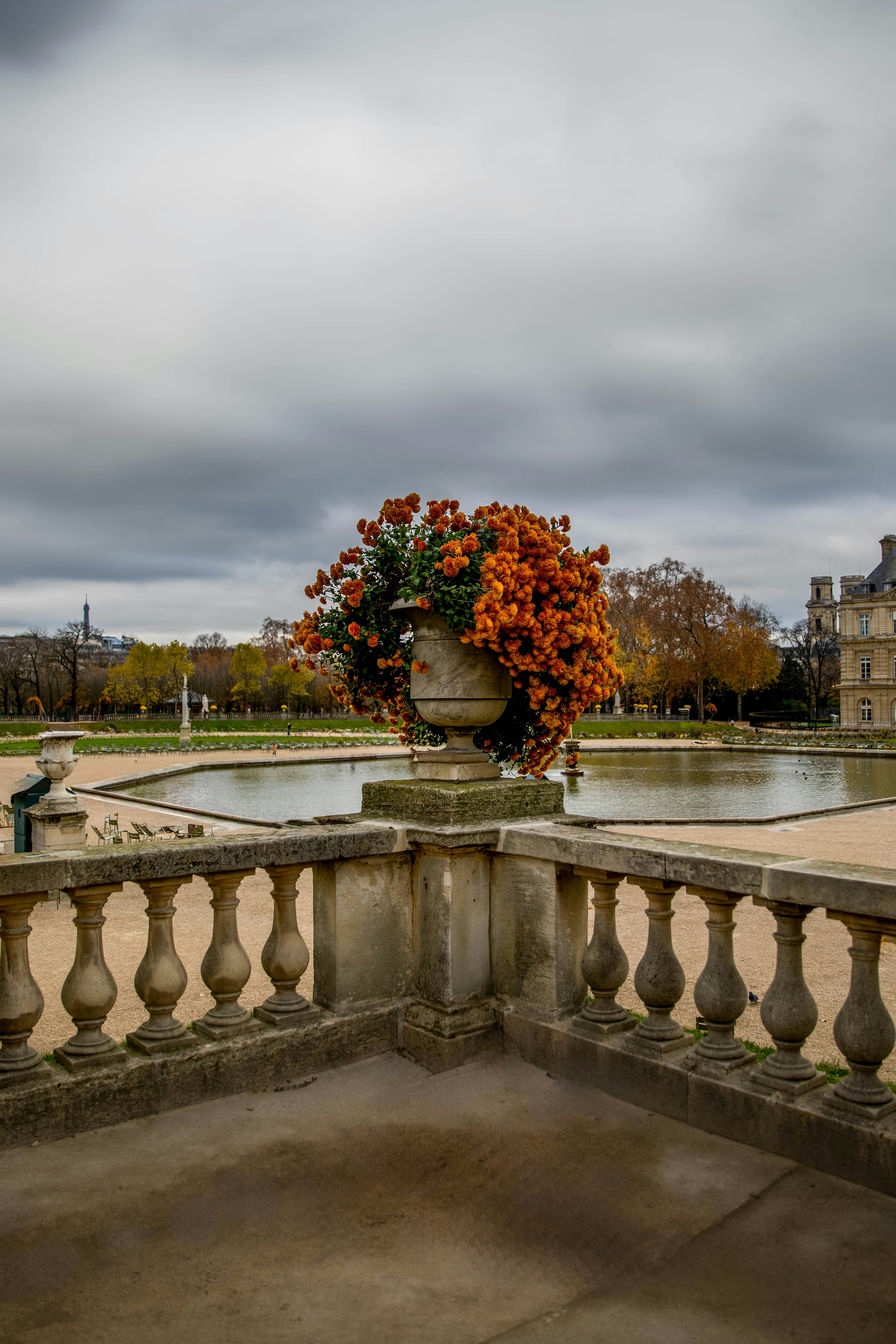 Autumn Terrace: Bronze Vase of Orange Blooms Guarding a Quiet Pond