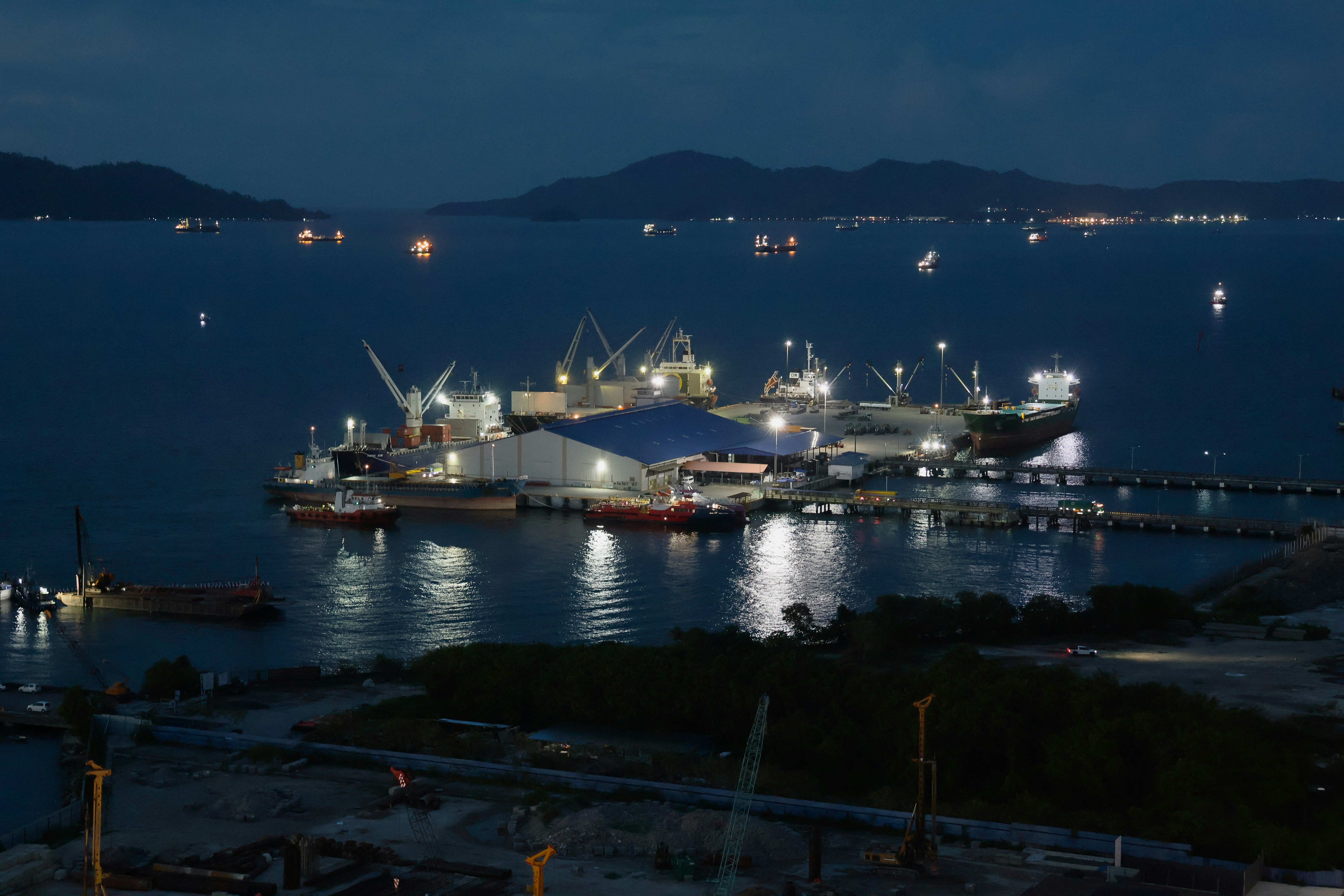 Moonlit Wharf: Reflections and Crane Lights on a Calm Harbor