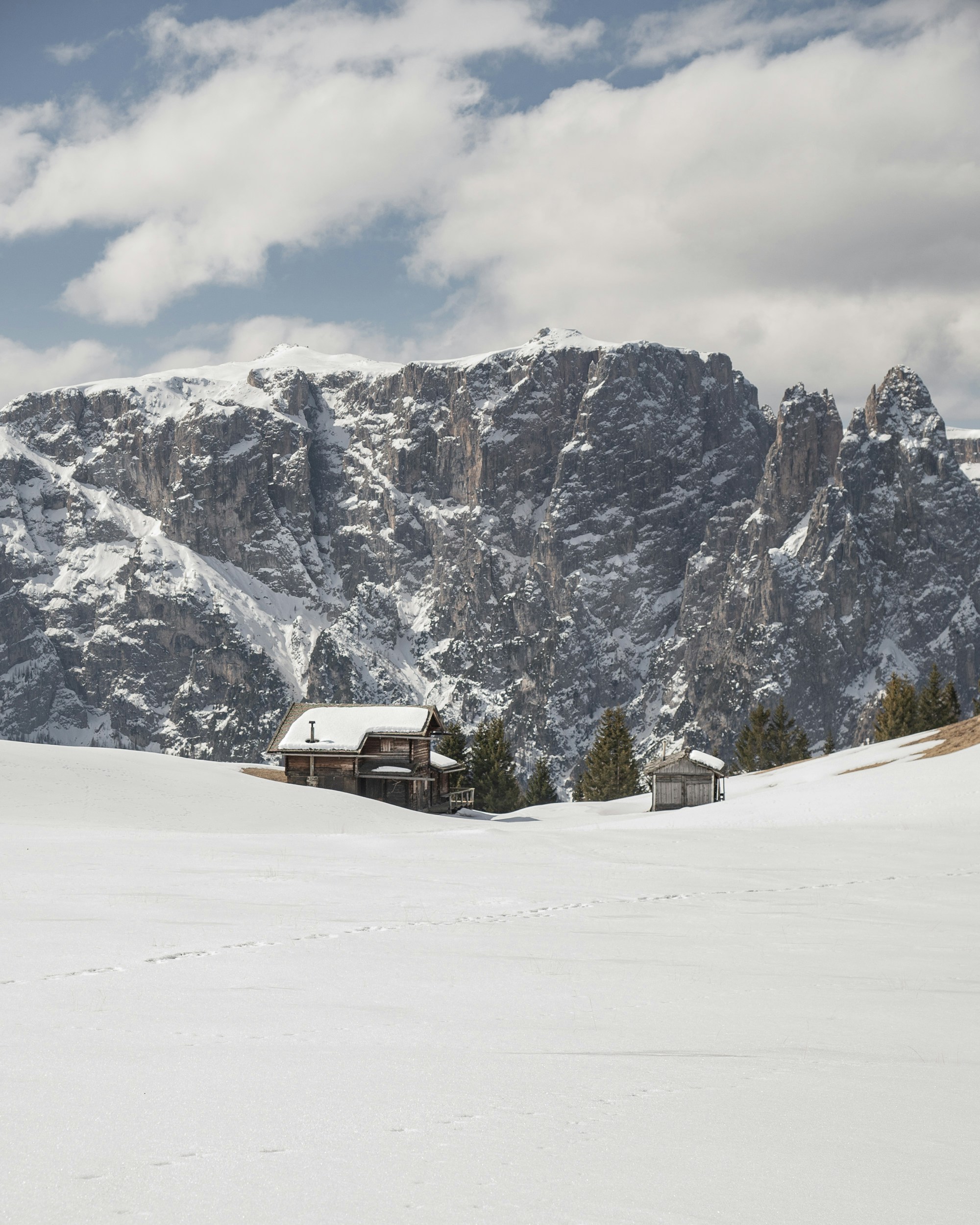 Snowbound Cabin Beneath Towering Alpine Cliffs