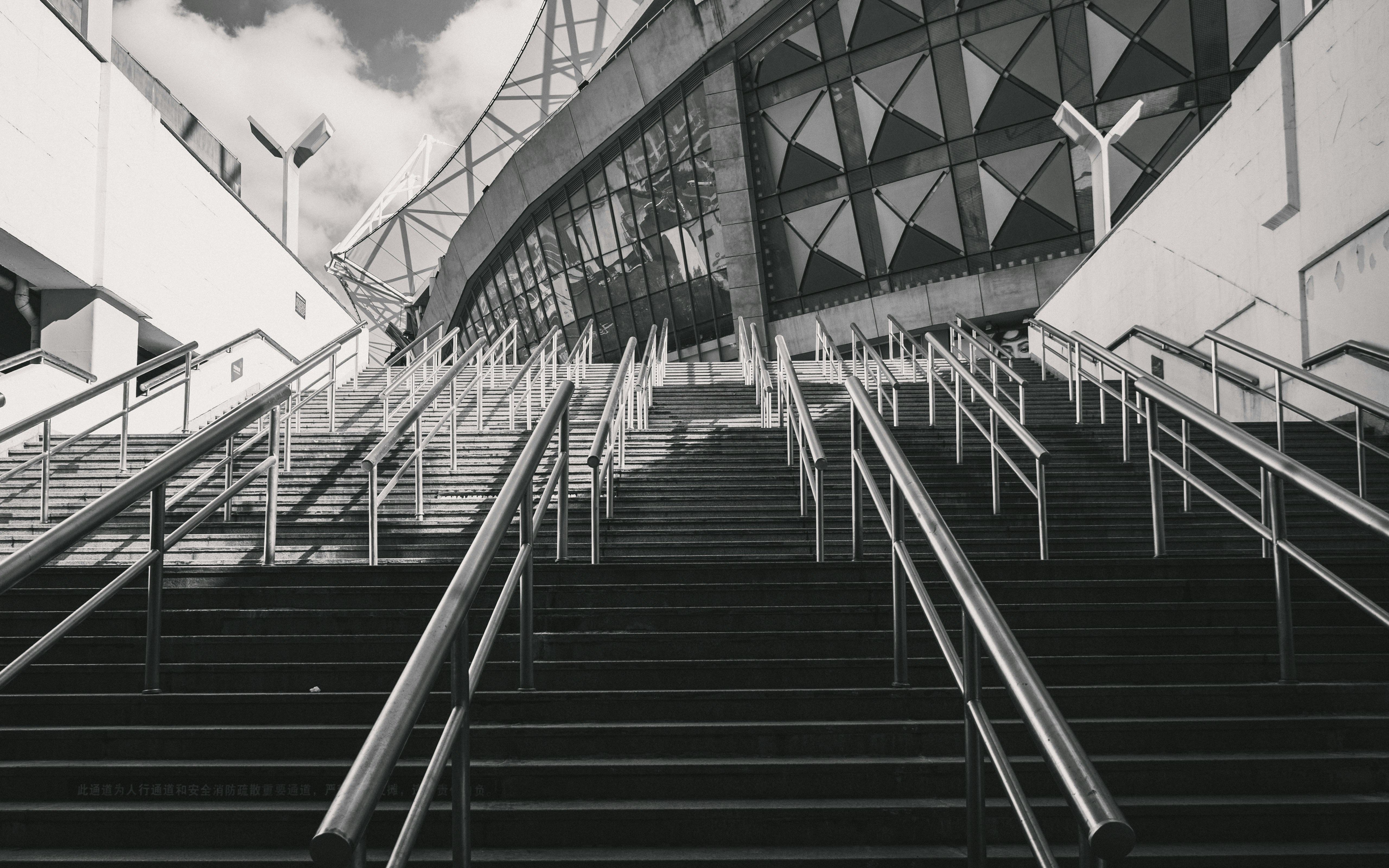 Staircase Convergence beneath a Silhouetted Glass Facade