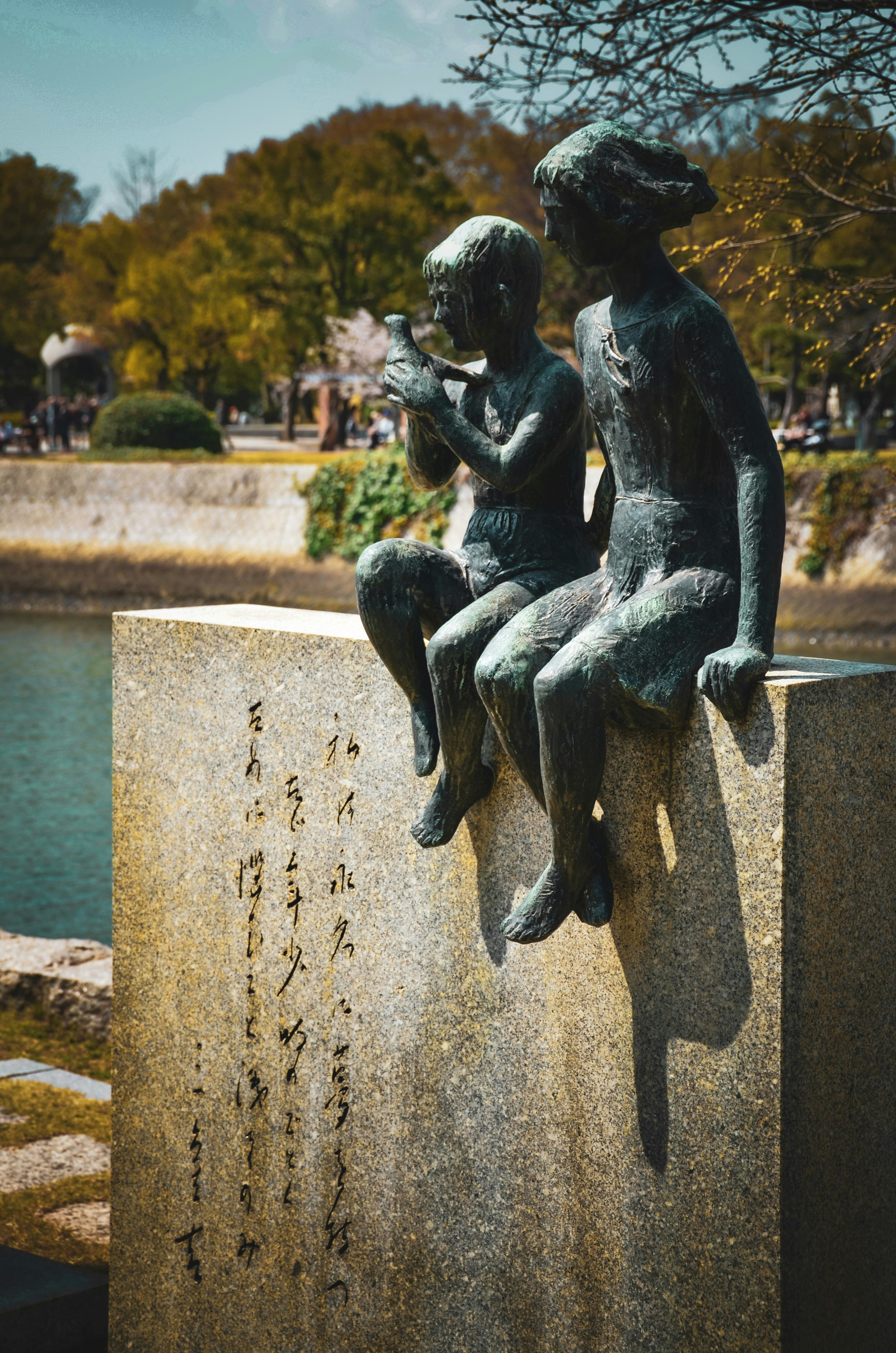Two Bronze Figures Perched on Stone—A Quiet Moment by the River