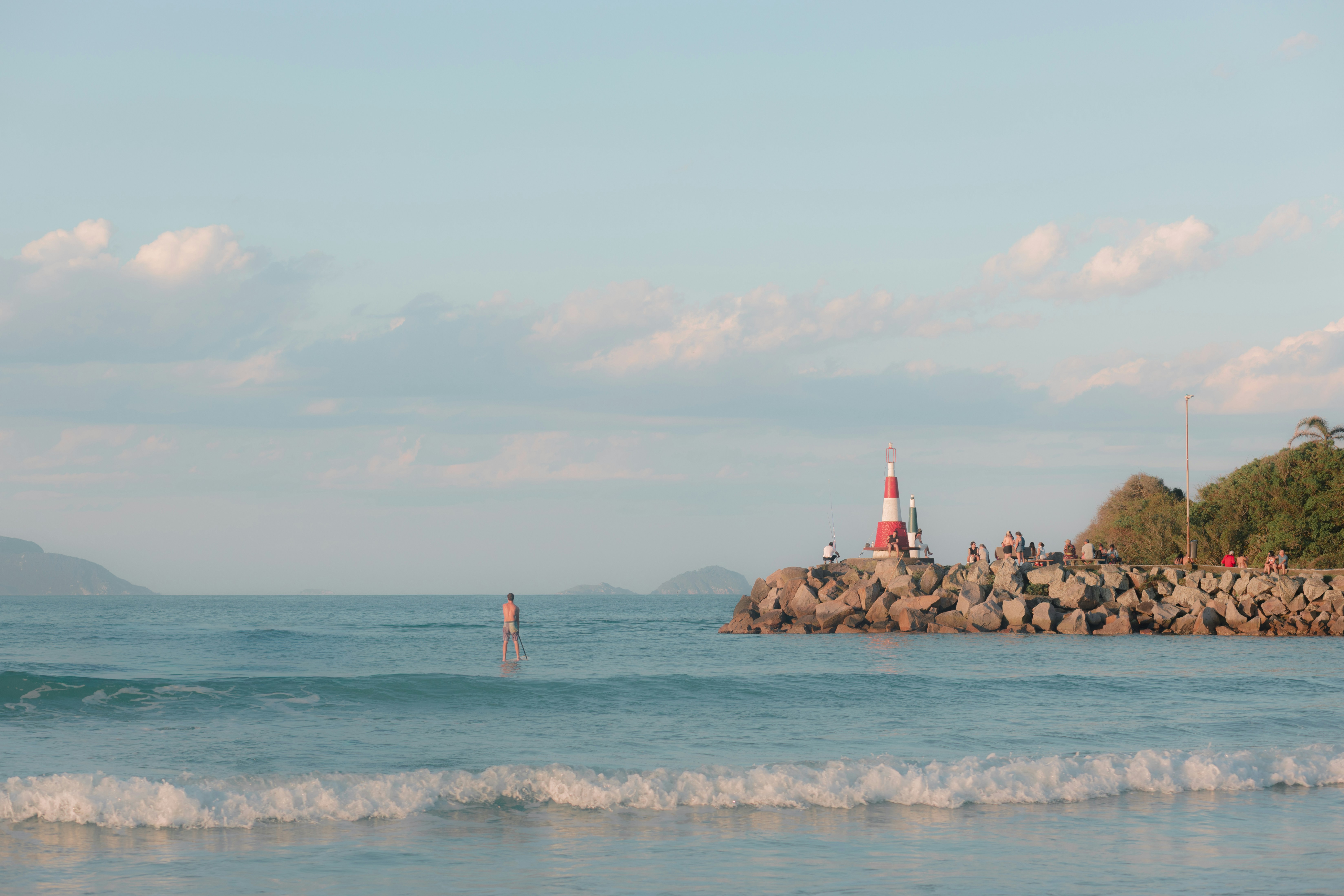 Lighthouse Break: People at the Pier Beneath a Quiet Coastal Sky