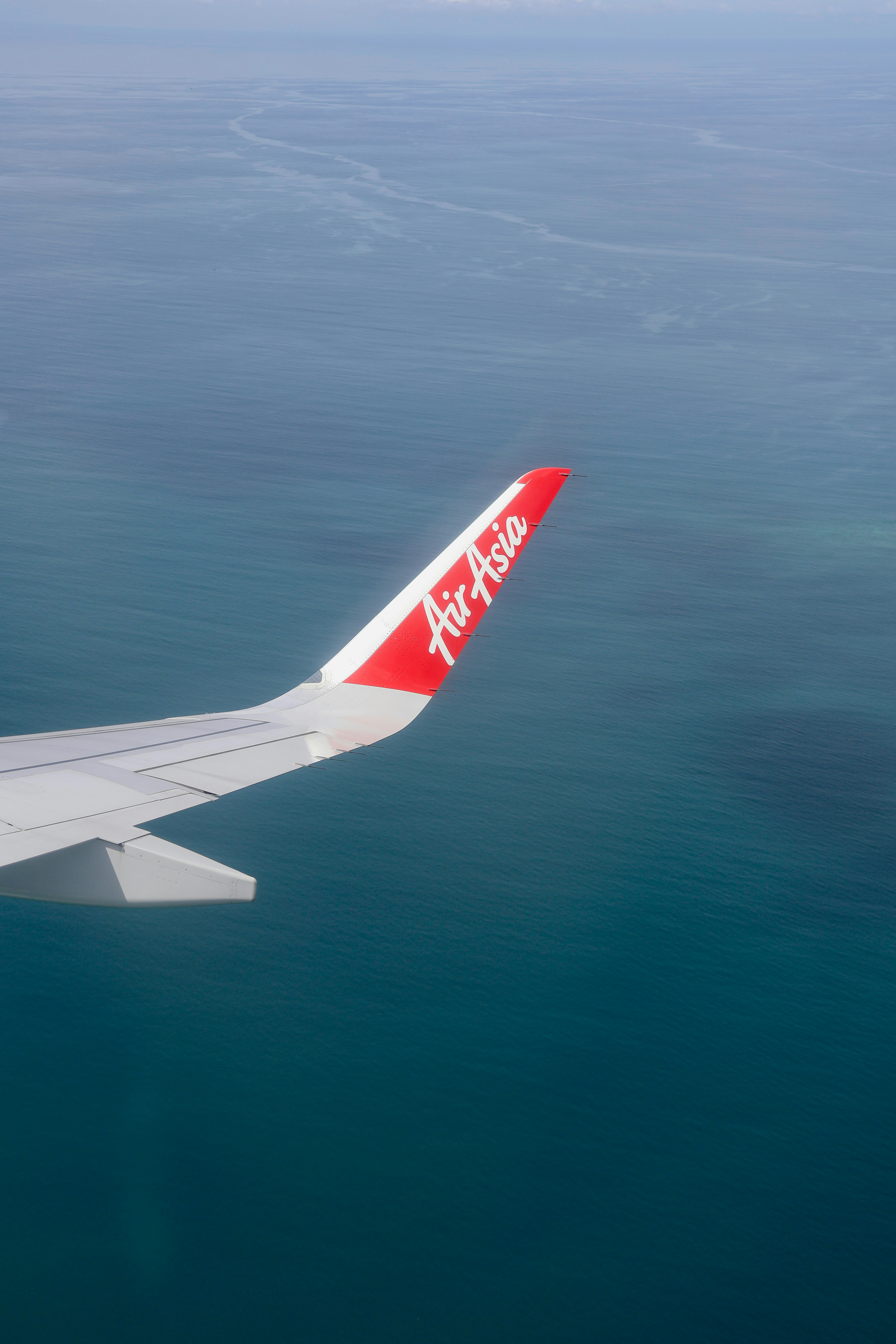 Red-Tipped Wing Arc Over Ocean: Airplane Window Perspective
