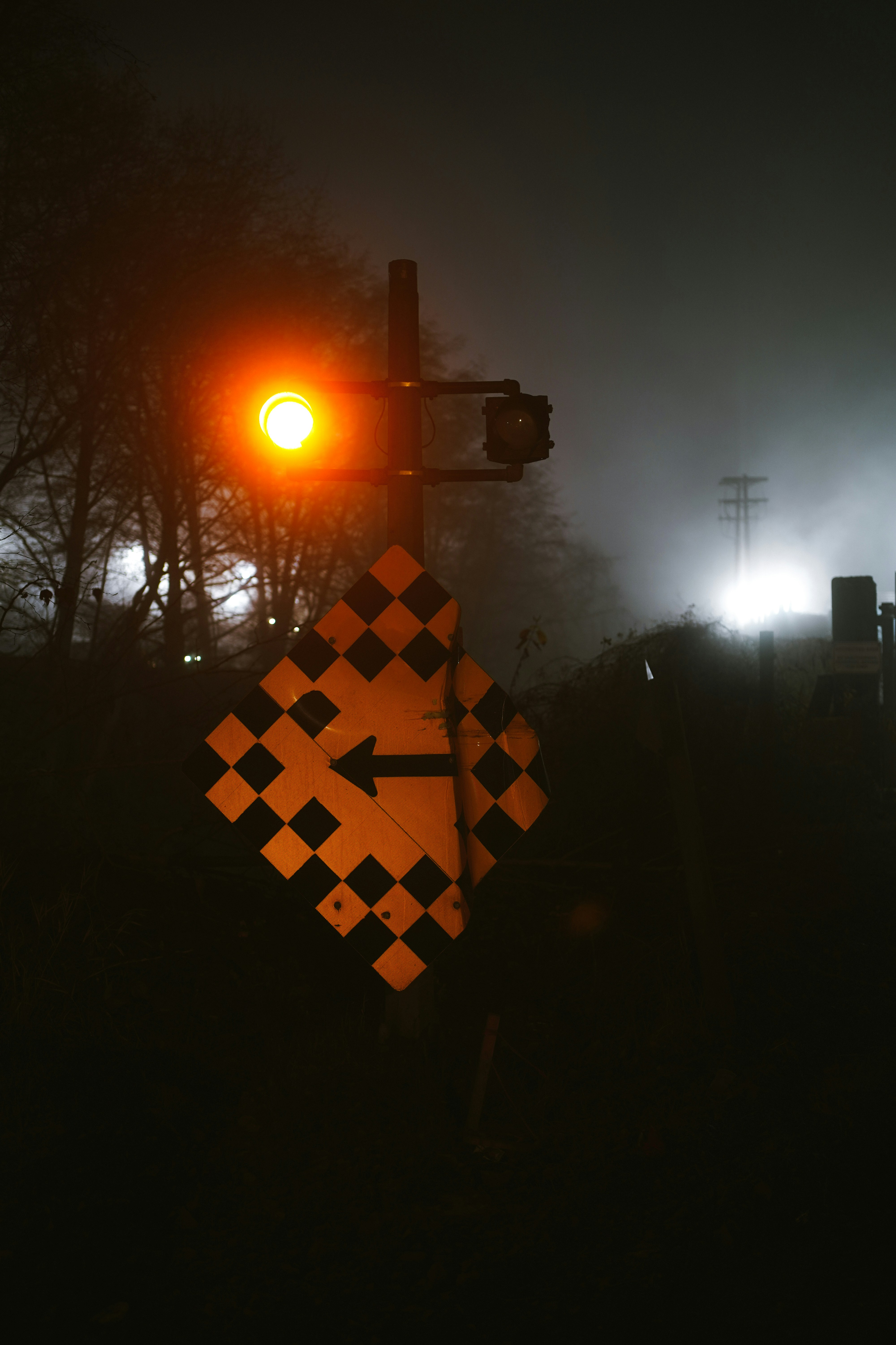Night Roadbound: The Dim Signal and Arrowed Sign in Fog