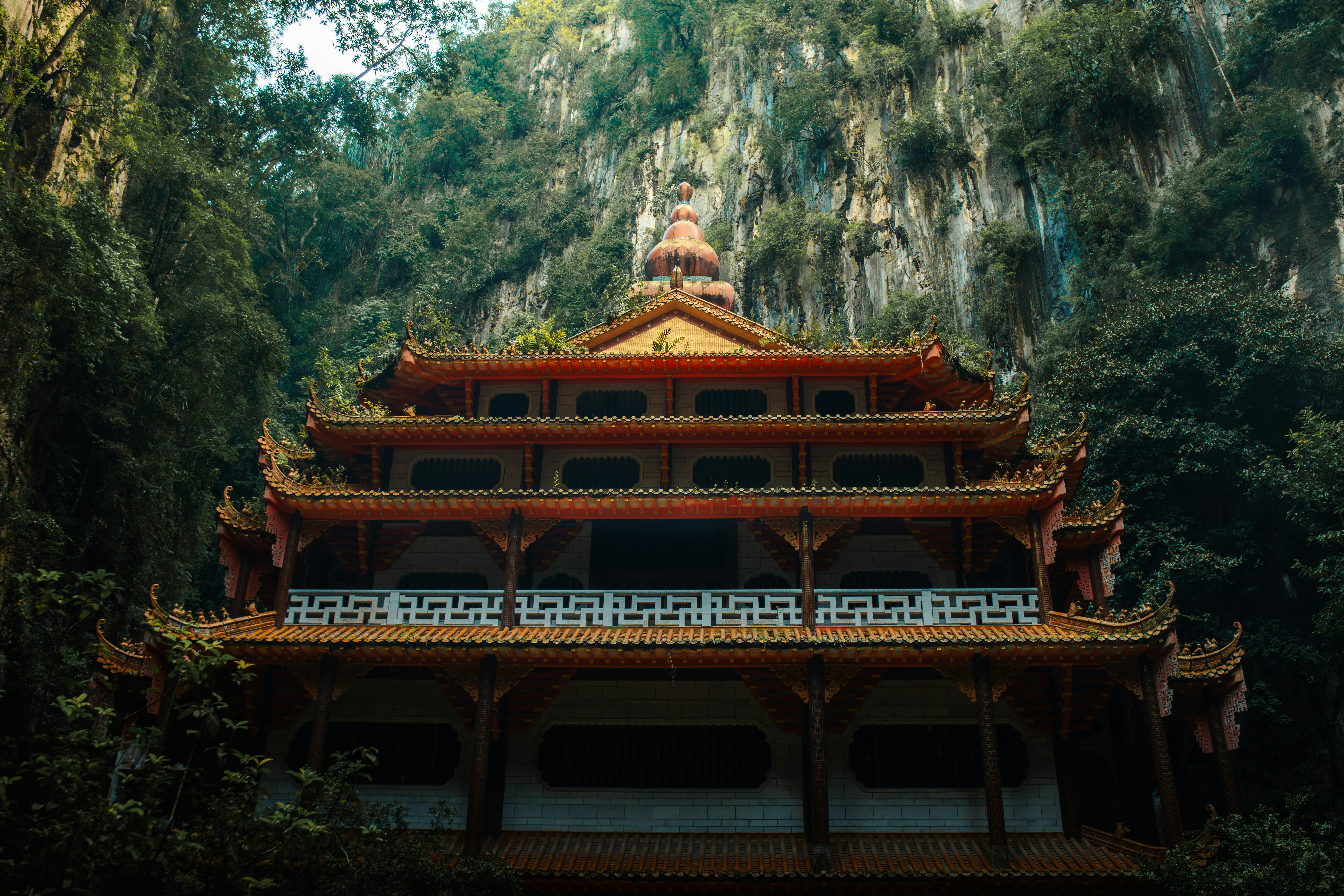 Red-Tiered Shrine Nestled Between Verdant Cliffs