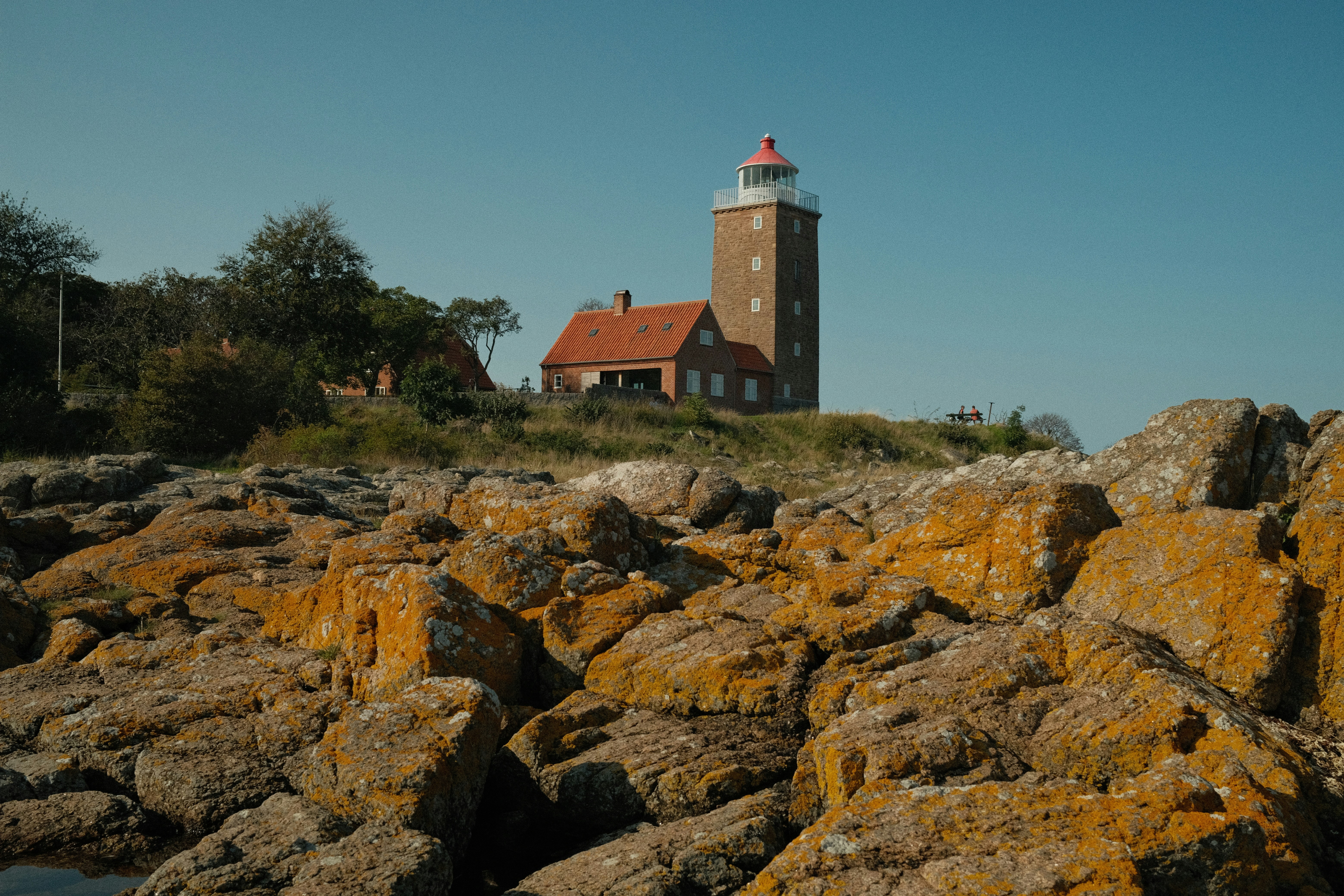 Lighthouse on the Ridge: Weathered Rocks Meet a Red-Topped Beacon