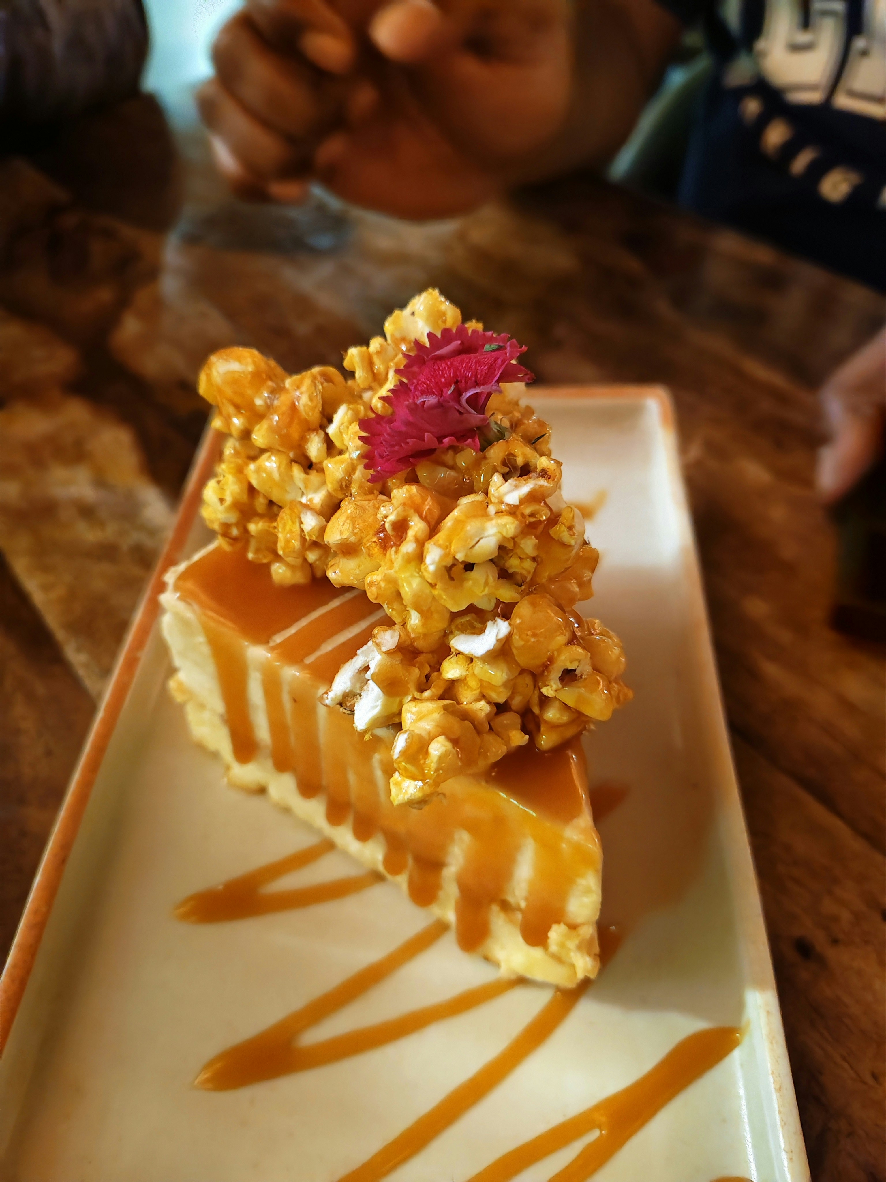 A slice of cheesecake topped with caramel and popcorn