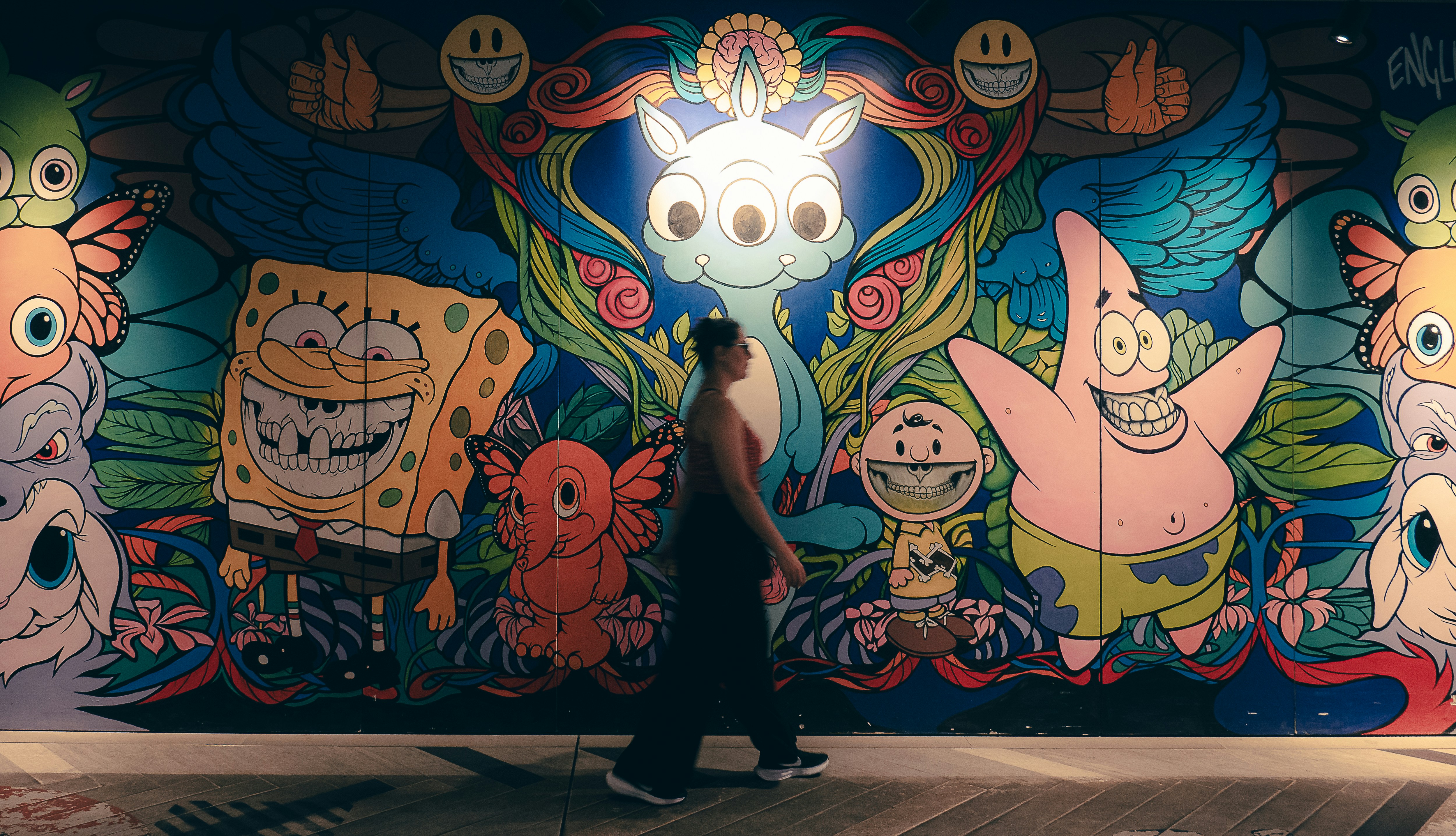 Person walks past colorful cartoon mural with spongebob characters ...