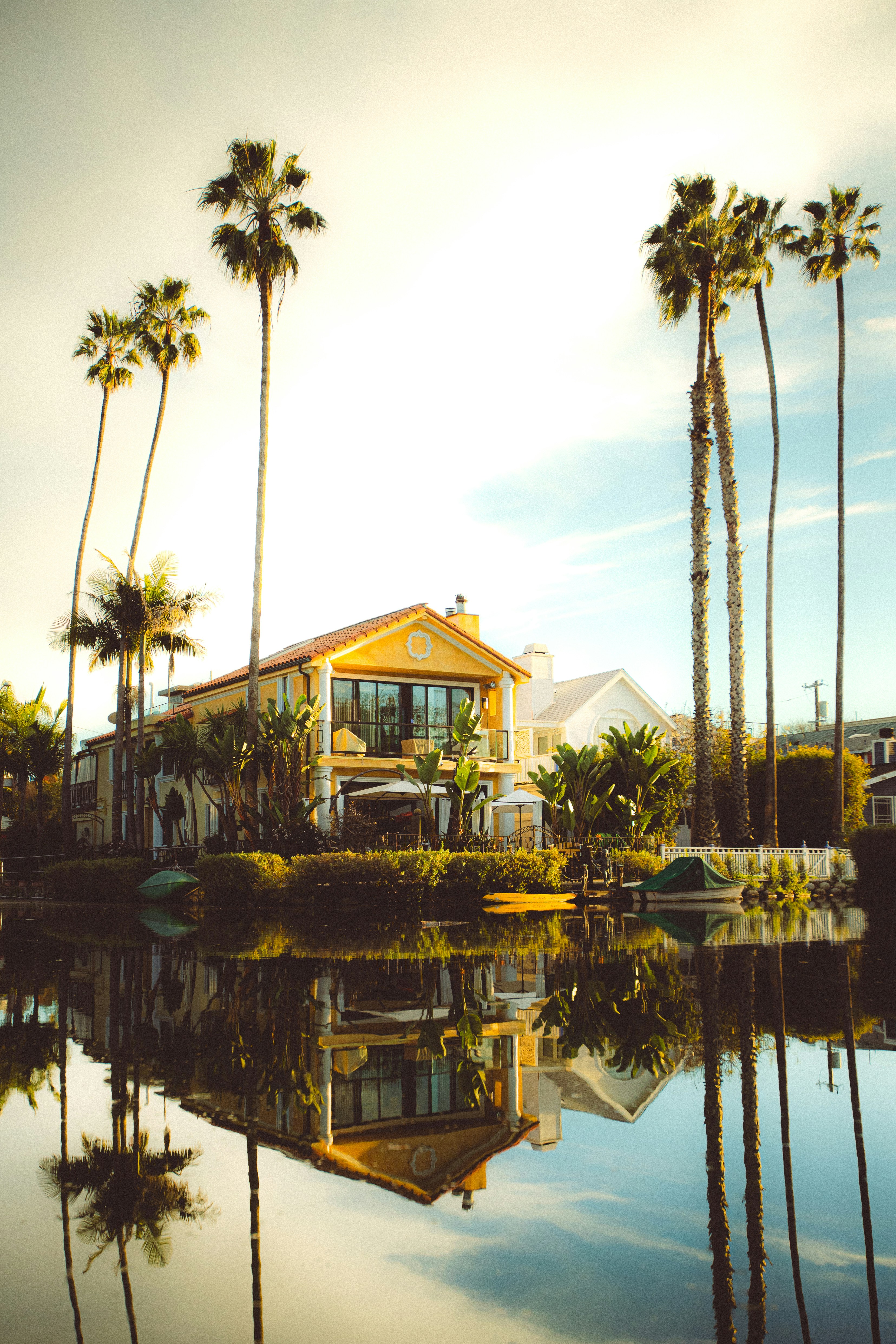 Sunlit Palm-Lined Villa Reflects in Tranquil Canal