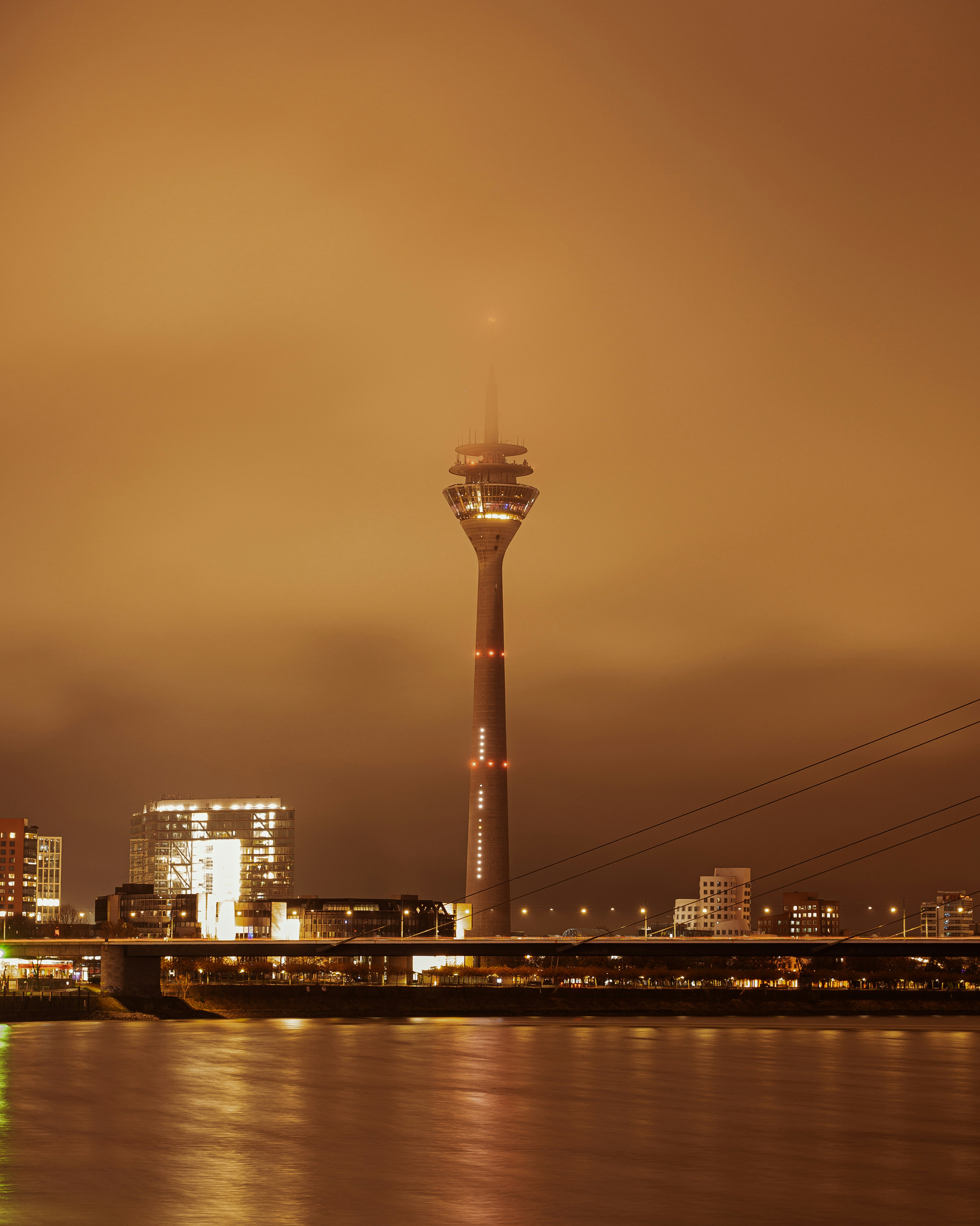 Midnight Beacon: A City Tower Rises Above the River Fog