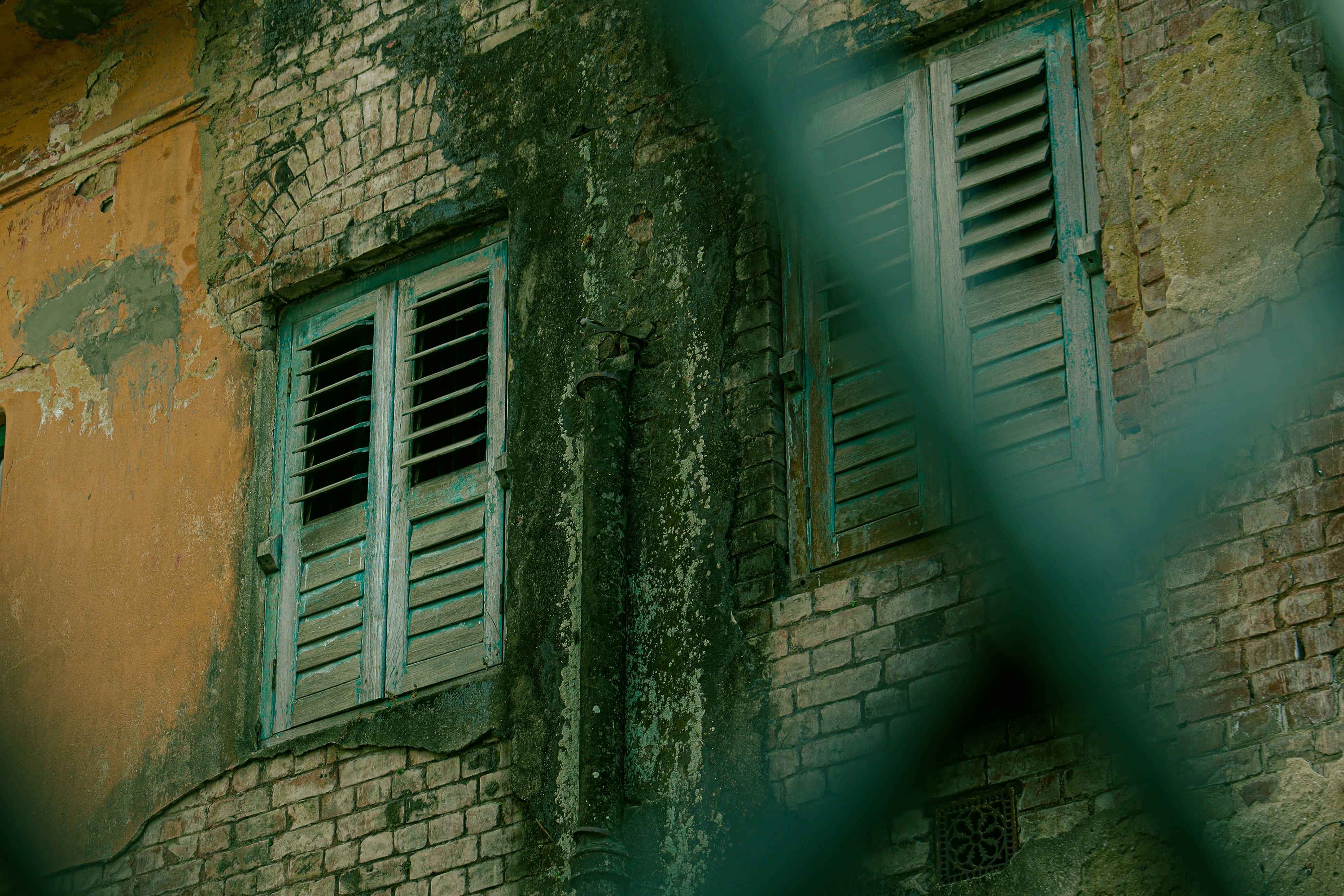 Hidden Facades: Weathered Brick and Shuttered Gaze