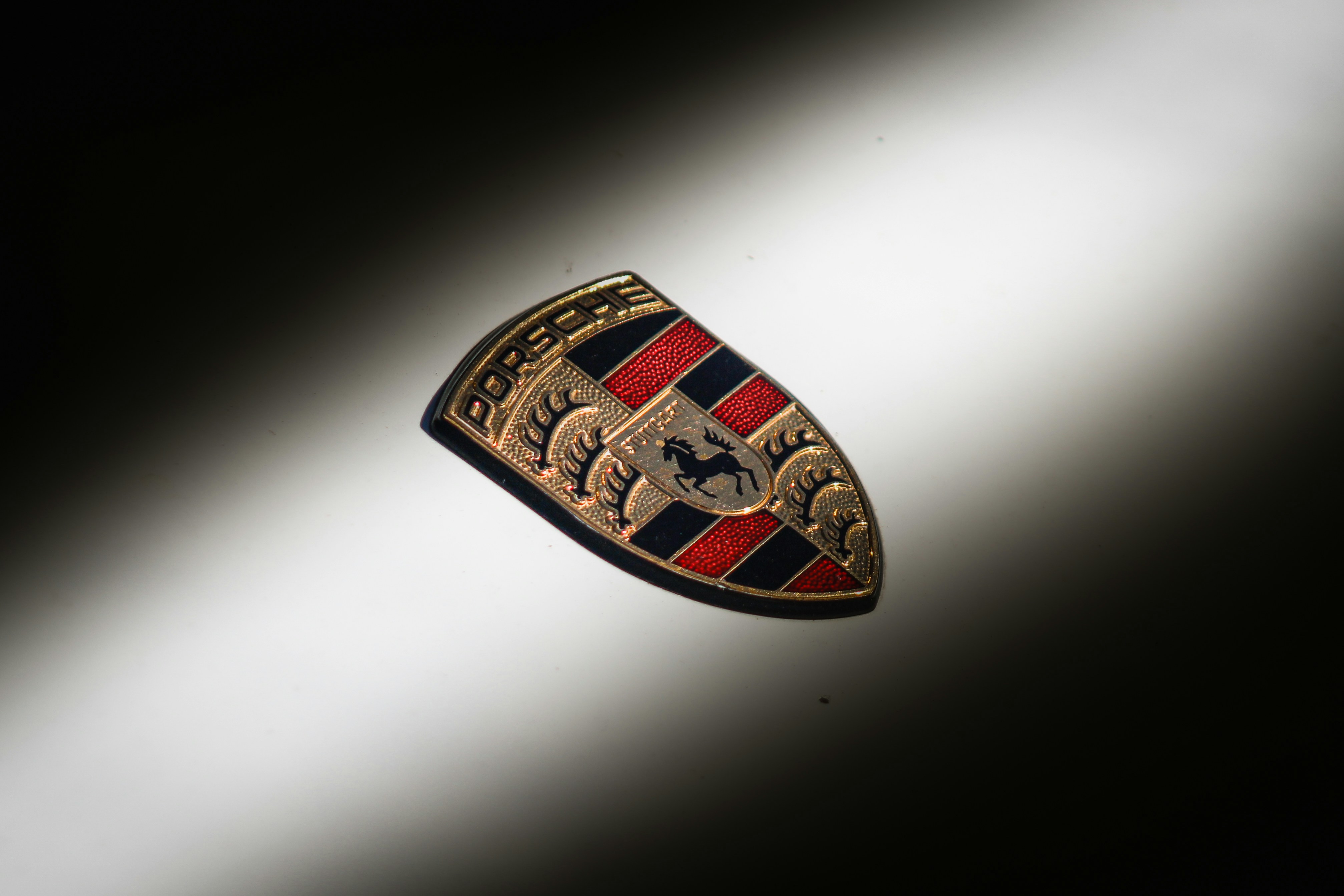 Spotlight on the Shield: Porsche Emblem Cast in a Narrow Beam