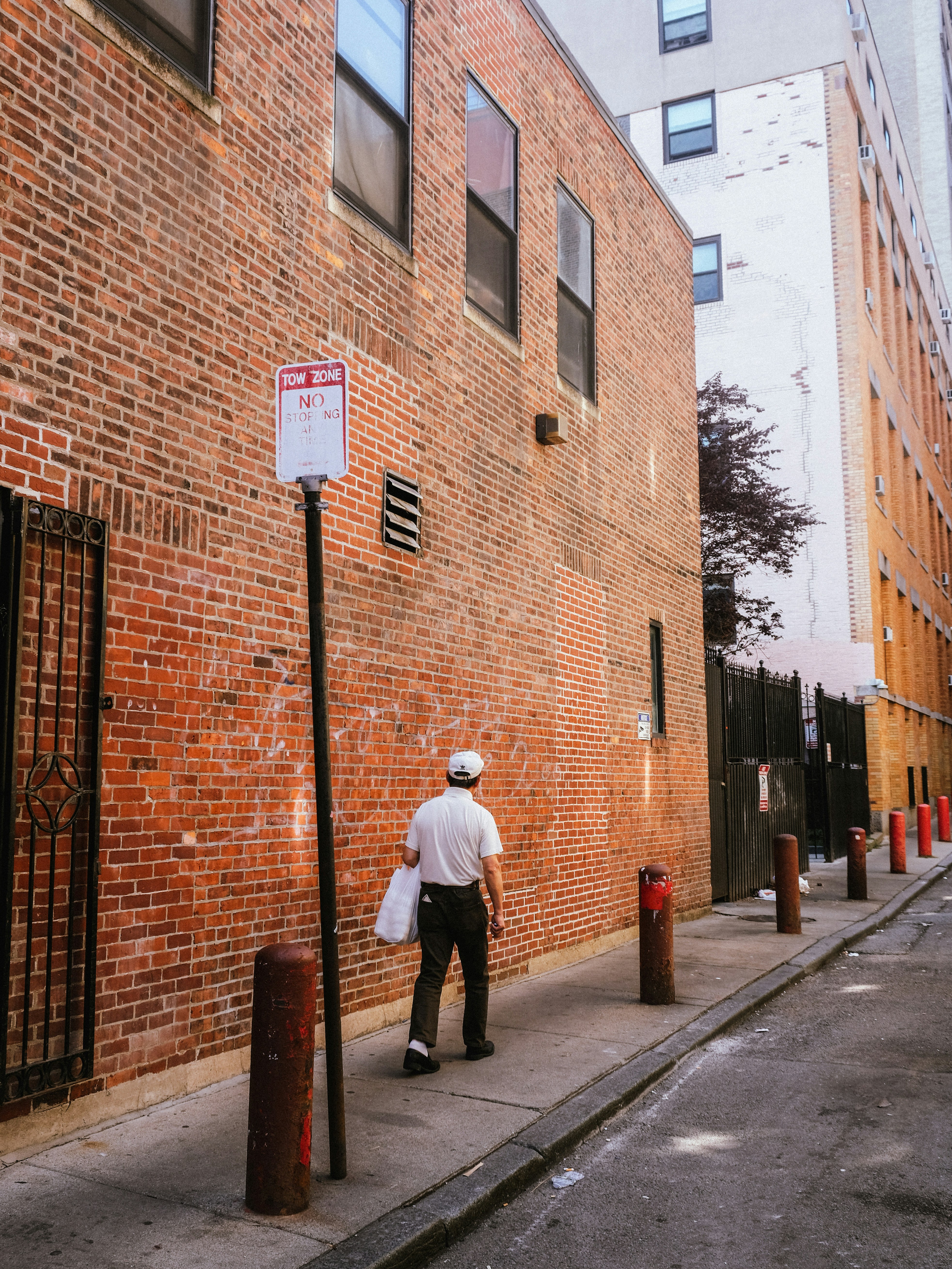 Urban Walk: A Man in White Descends a Brick Alley