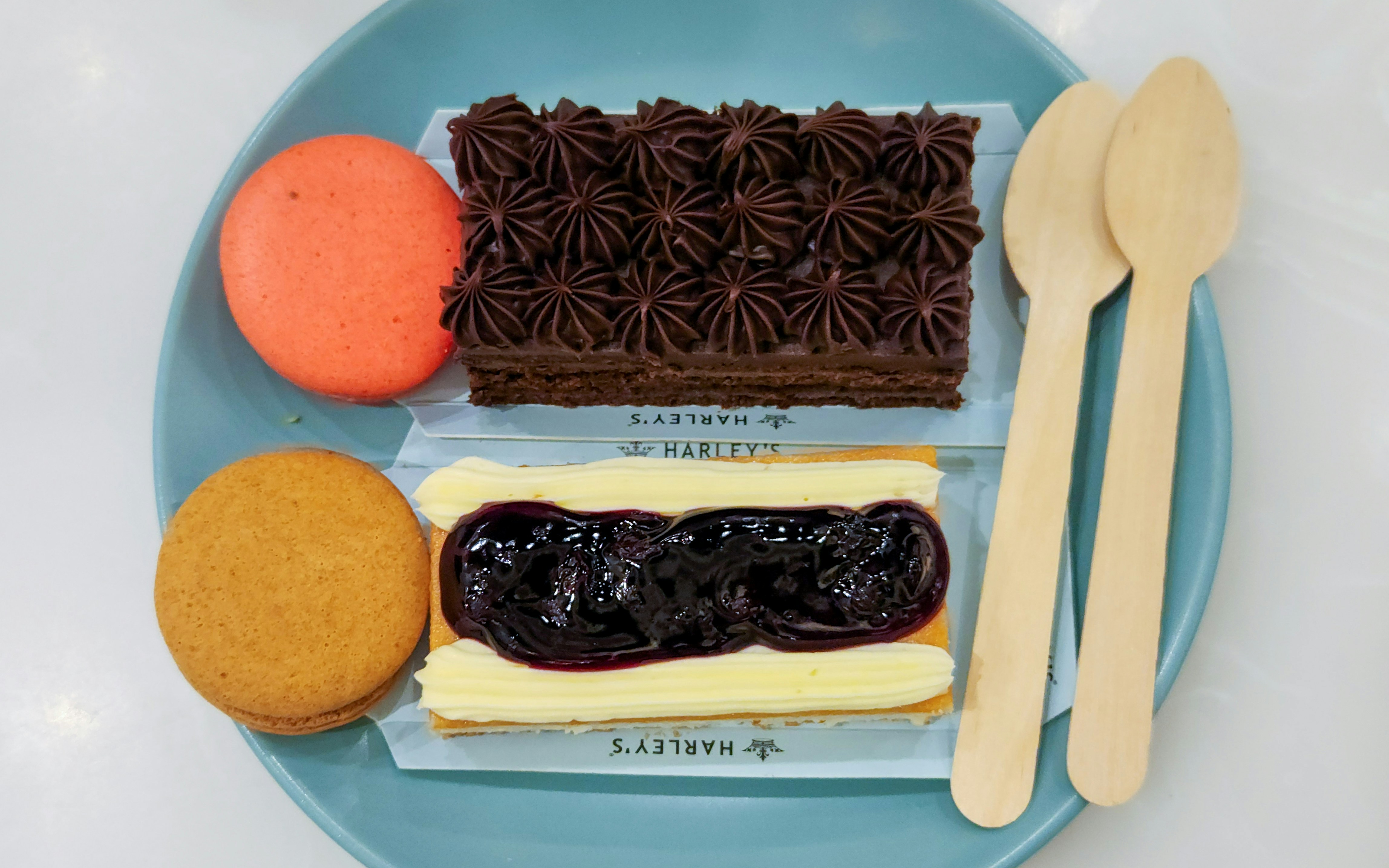 Sweet Trio on a Turquoise Plate: Chocolate Rectangles, Creamy Cheesecake, and Citrus Macaron