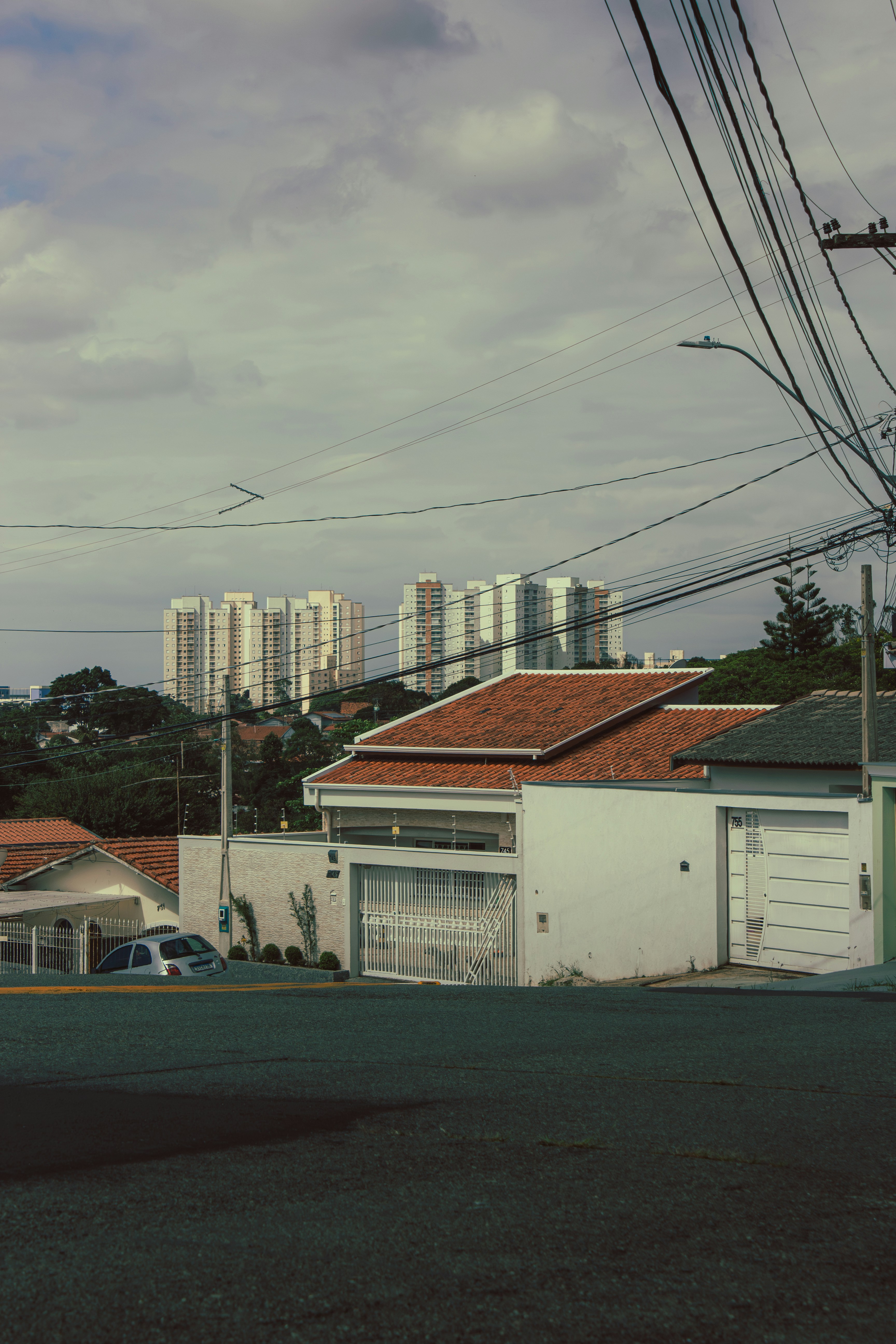 Suburban Street Converges with Skyline: Wires, Houses, and distant High-Redemption Towers