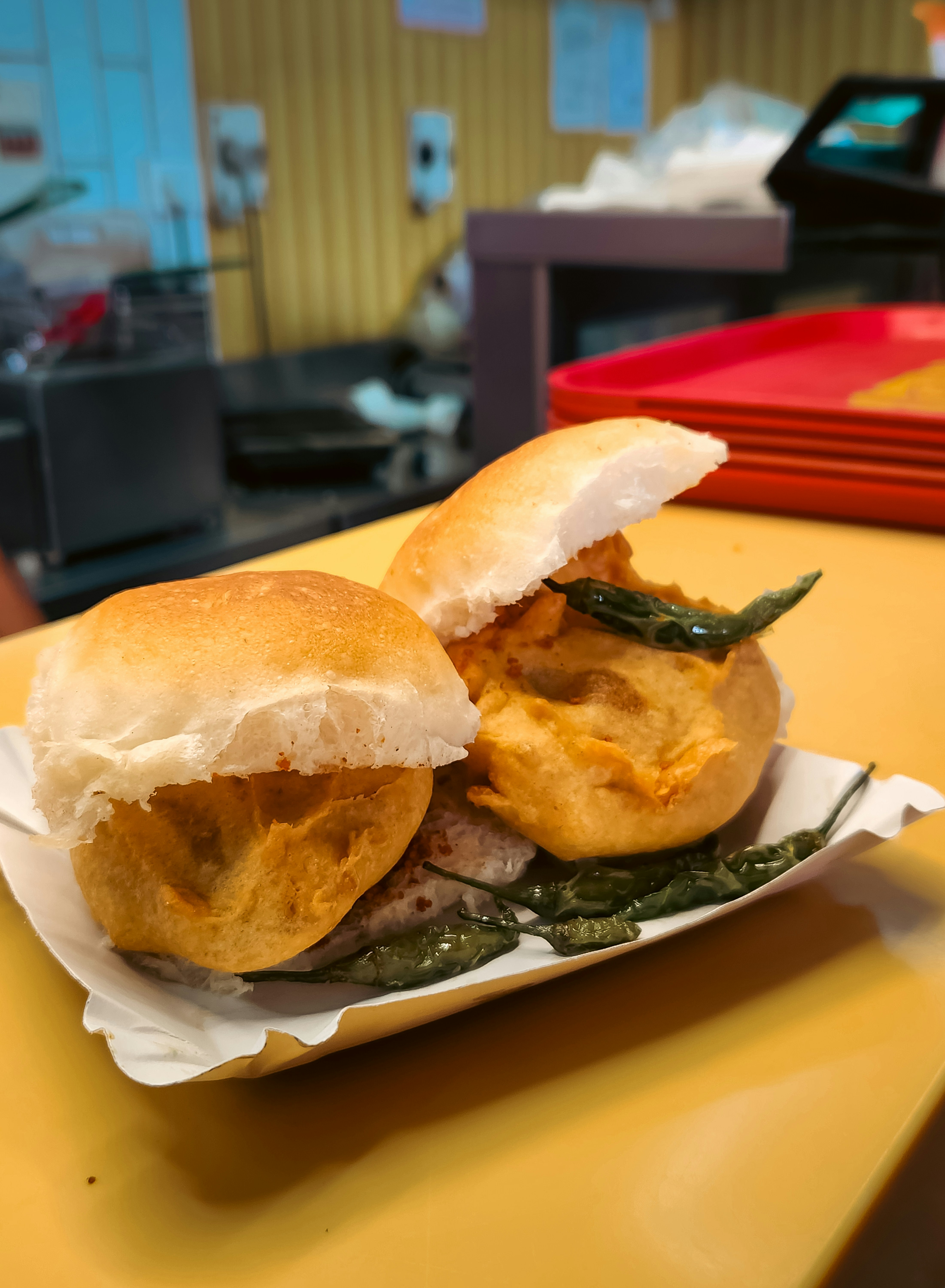 Golden Bites: Two crispy sliders resting on a paper tray amidst a busy diner backdrop