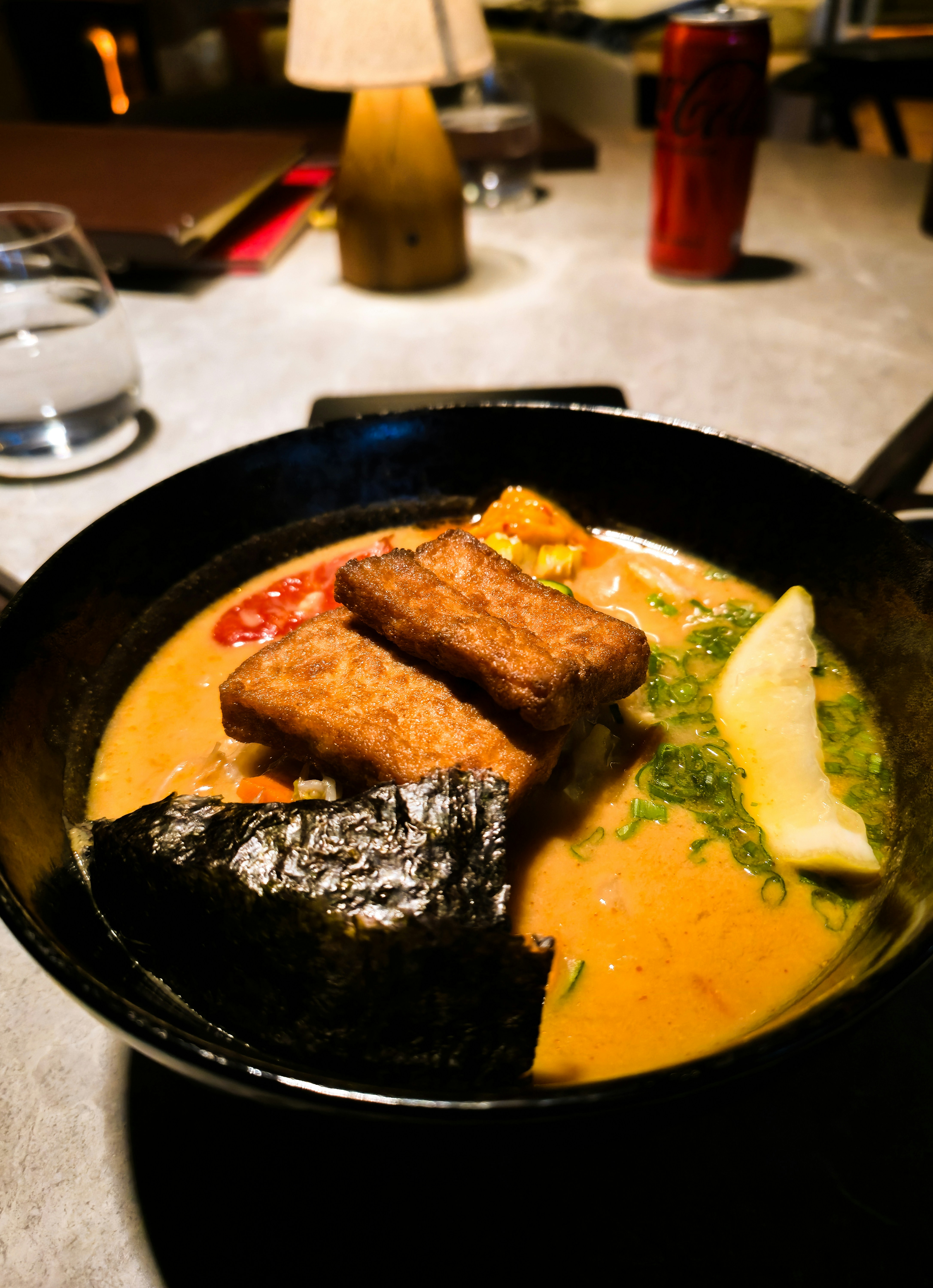Charred Pork and Seaweed in a Creamy Ramen Bowl under Ambient Restaurant Light