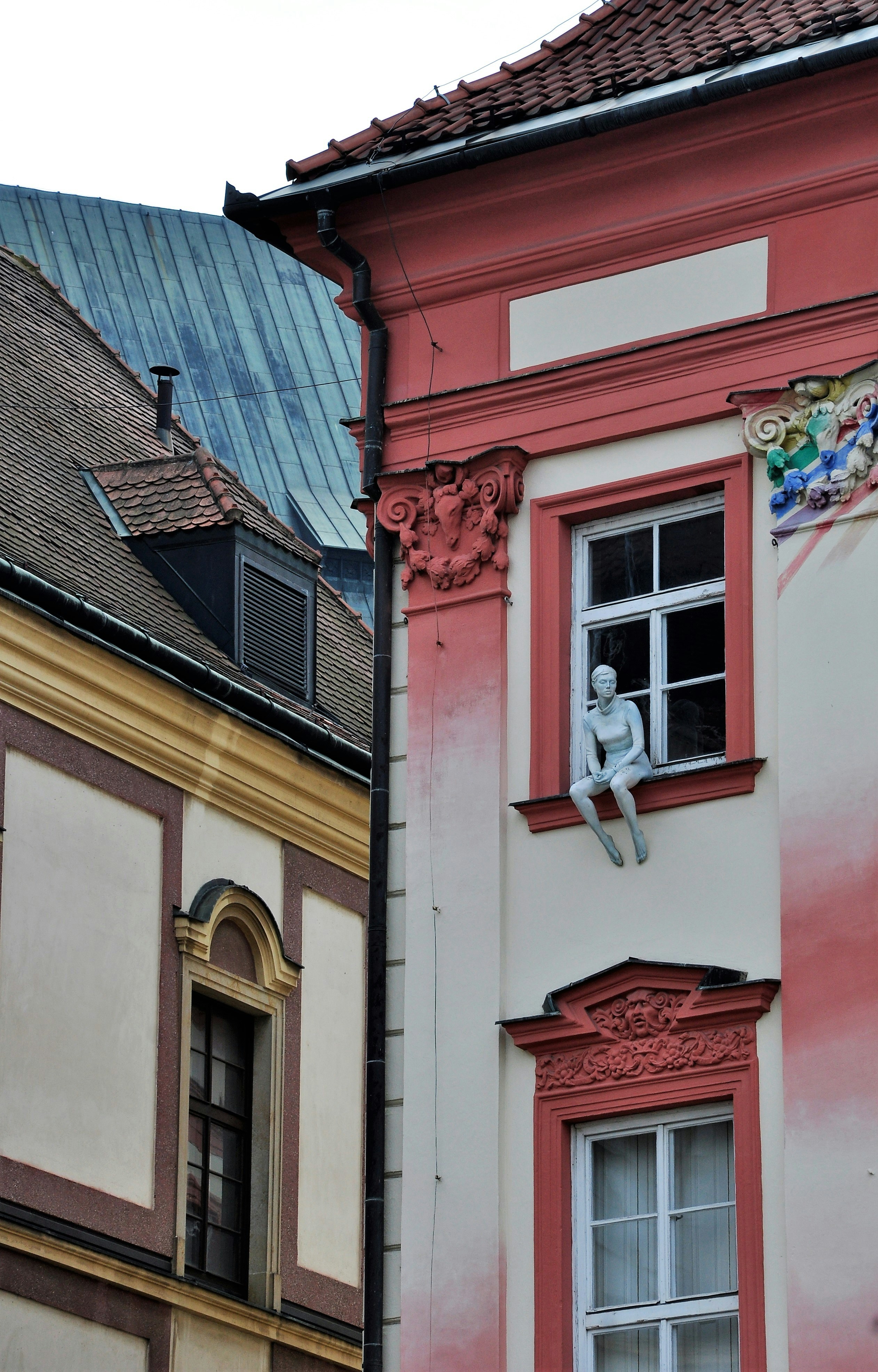 Figurine at the Window: A Quiet Street Portrait in Red and Peach