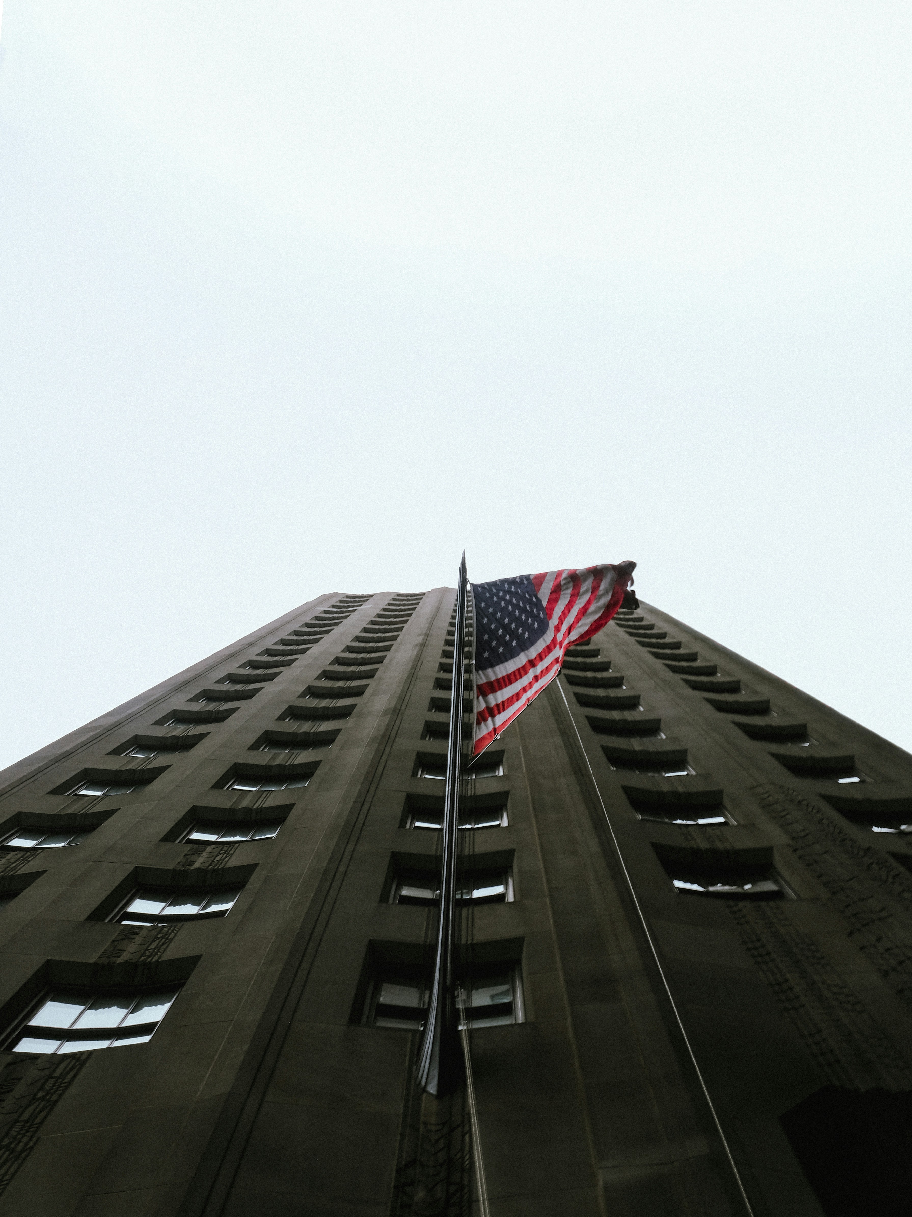 Flag Rising on a Skyscraper: An American Beacon Against the Sky