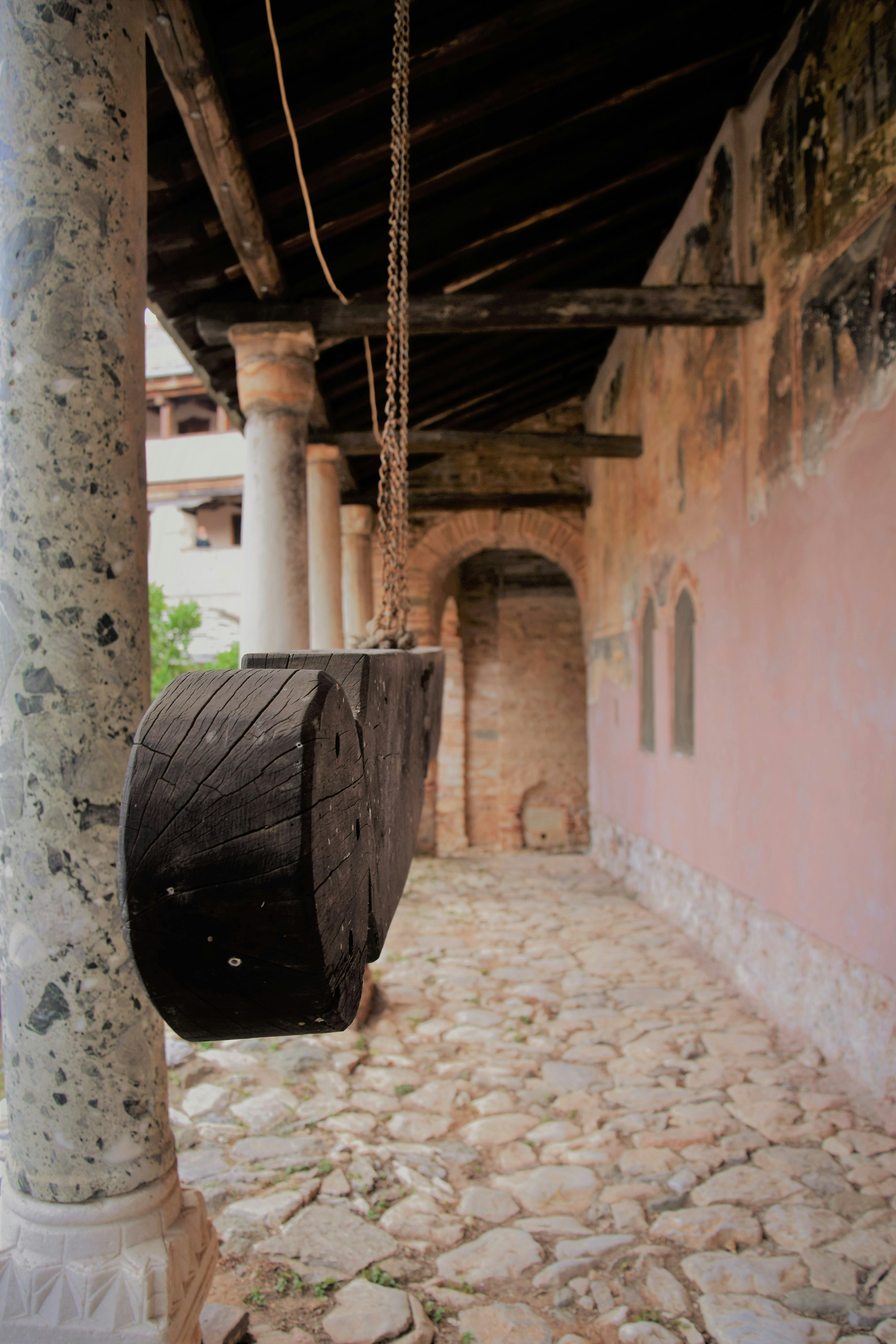 Worn wooden swing in a sunlit adobe corridor