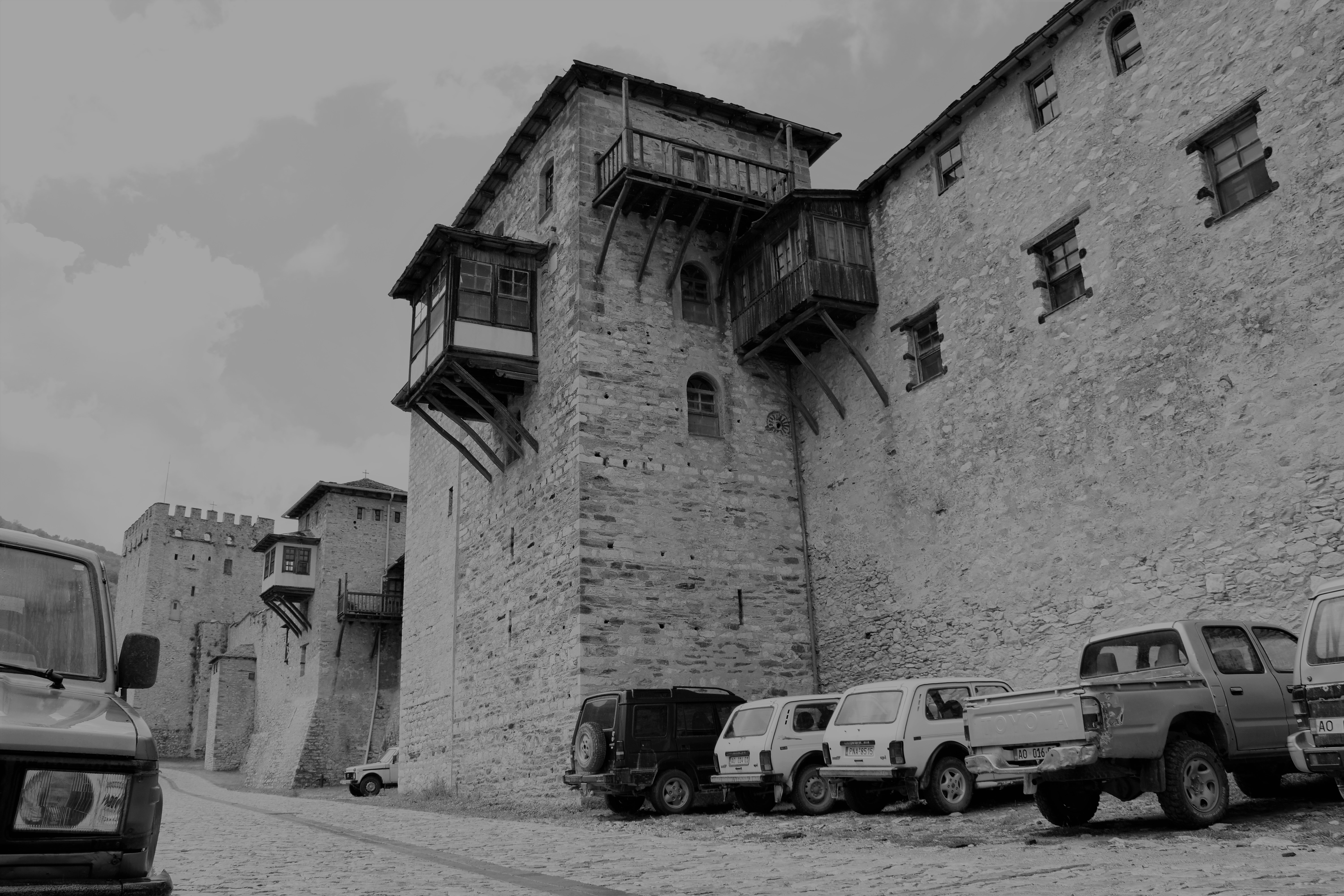 Medieval Courtyard Facade: Cars Beside the Stone Citadel