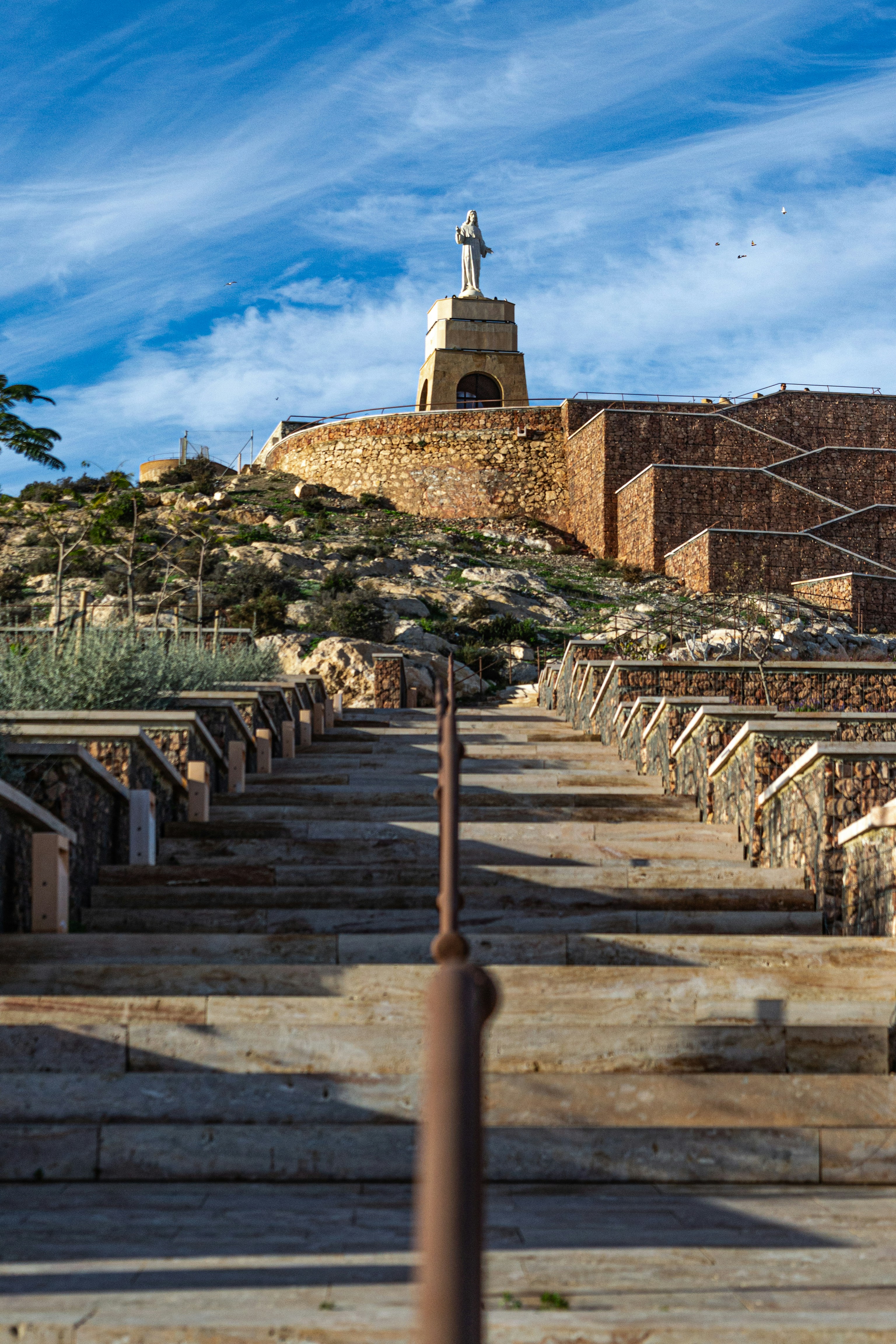 Stone Stairway to the Statue: A coastal ascent under a vivid sky