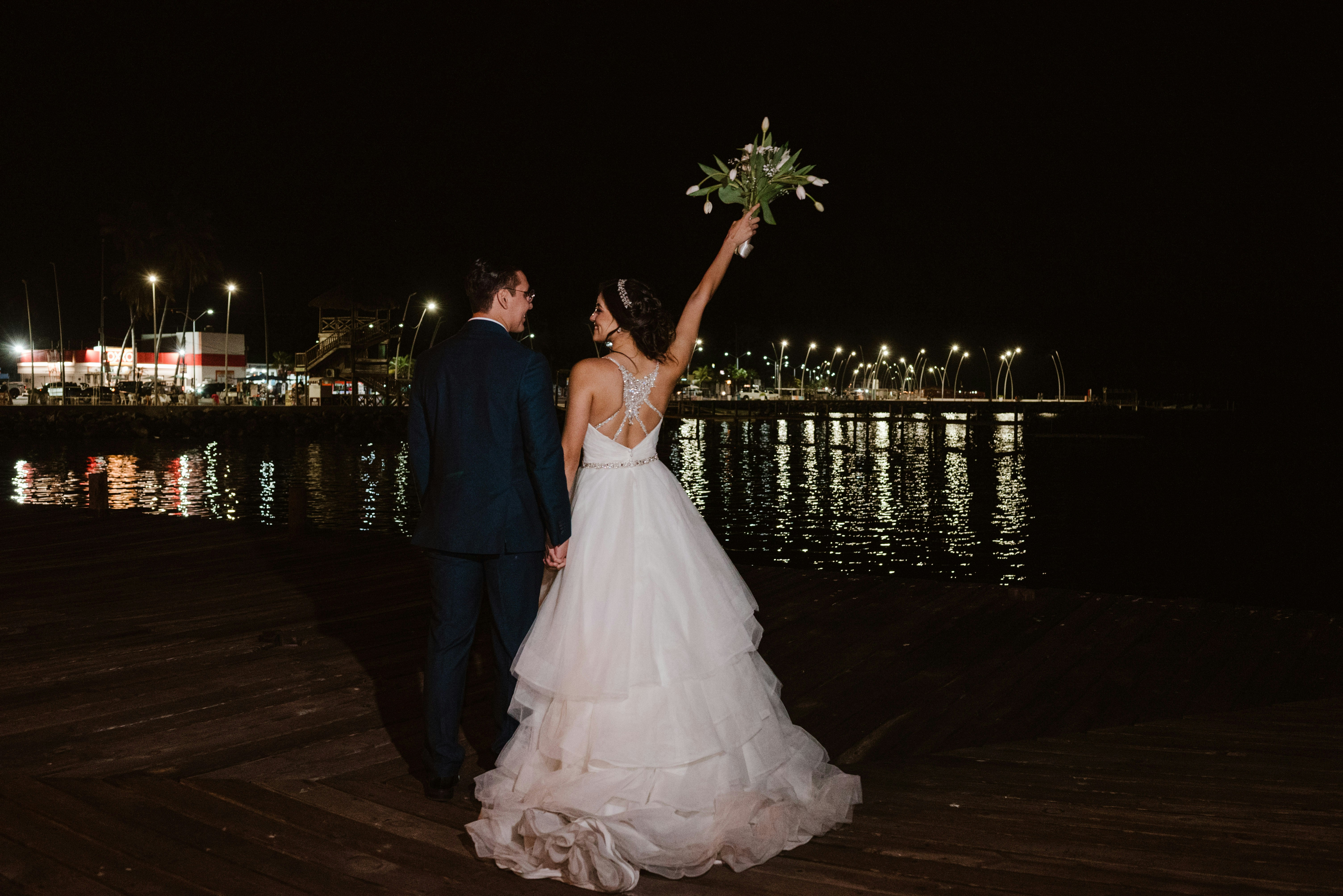 Bride Lifts a Bouquet Under Night Harbor Lights