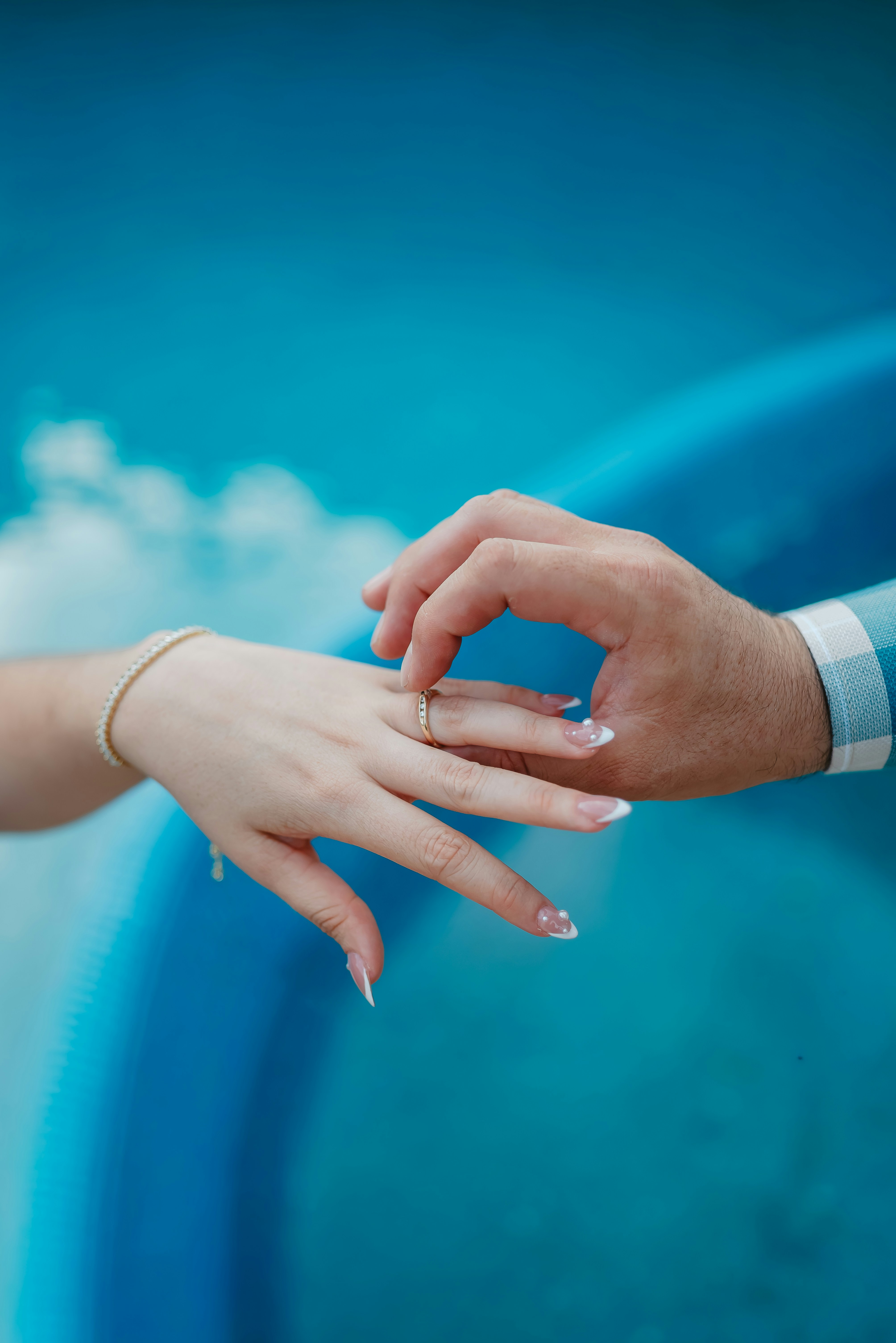 Hands of Promise: A Ring Exchange Against a Blue Backdrop