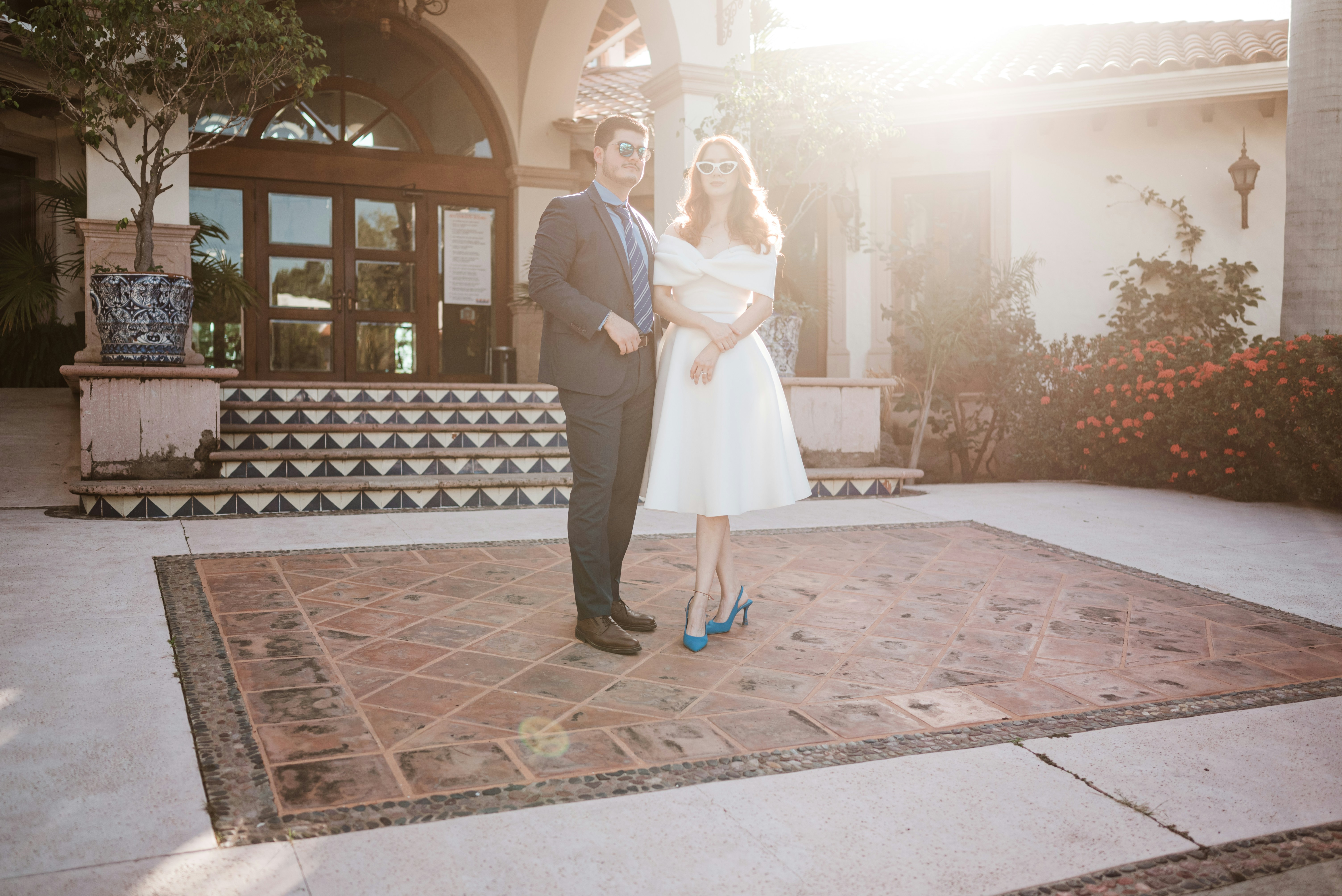 Sunlit vows: a stylish couple framed on a tiled courtyard