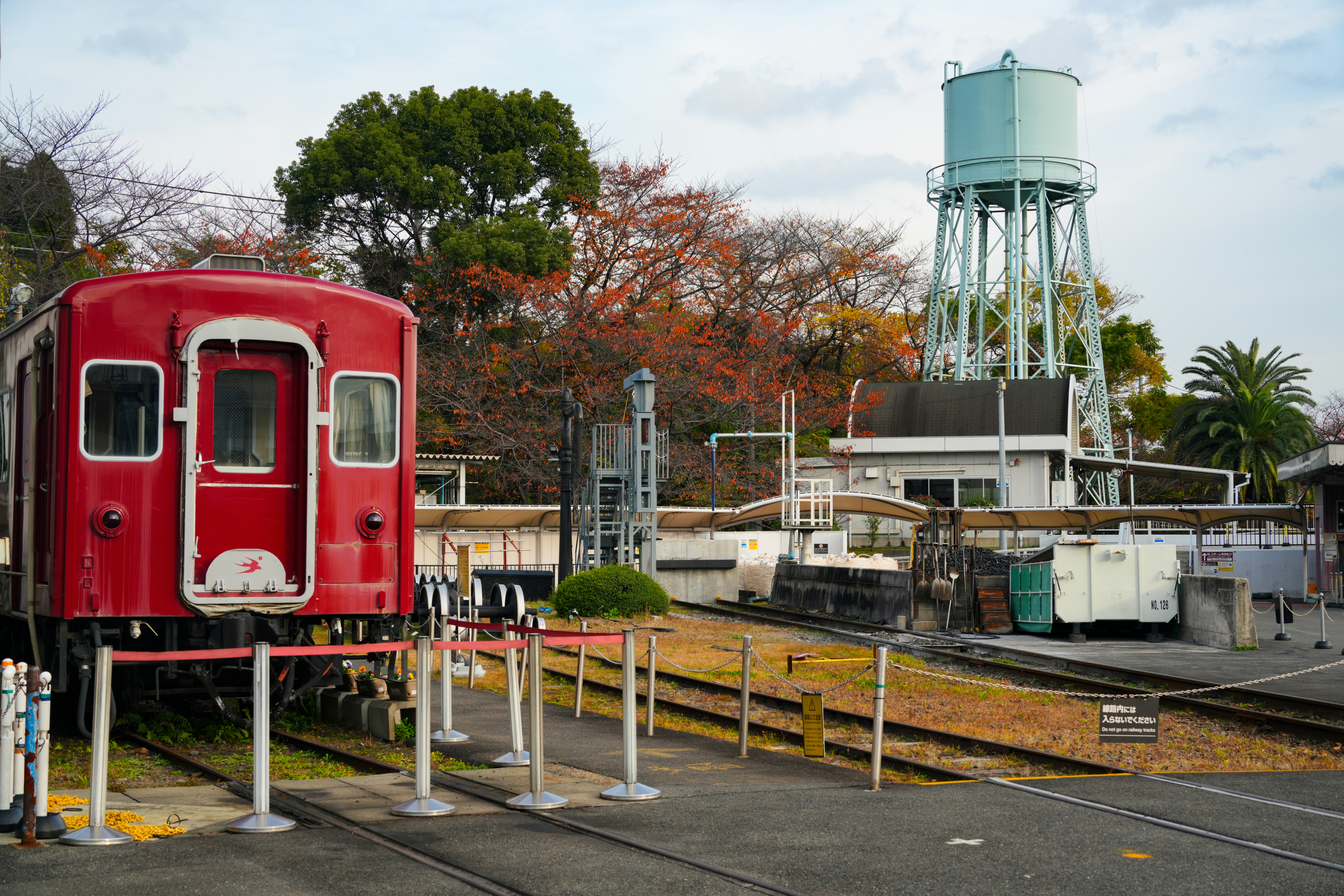 Red Railcar at a Quiet Yard With Autumn Trees and Water Tower