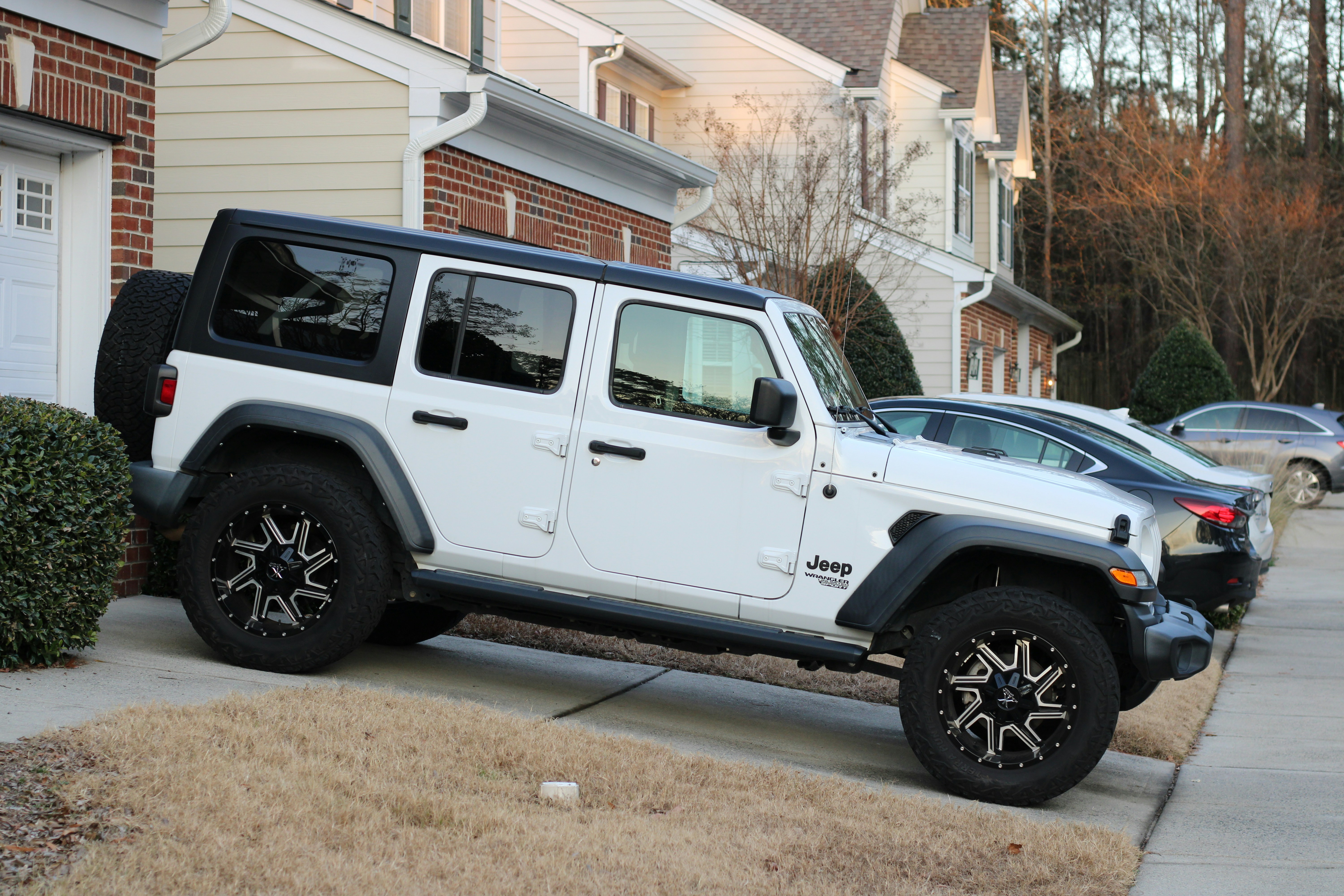 White Jeep Wrangler Tilted on a suburban driveway