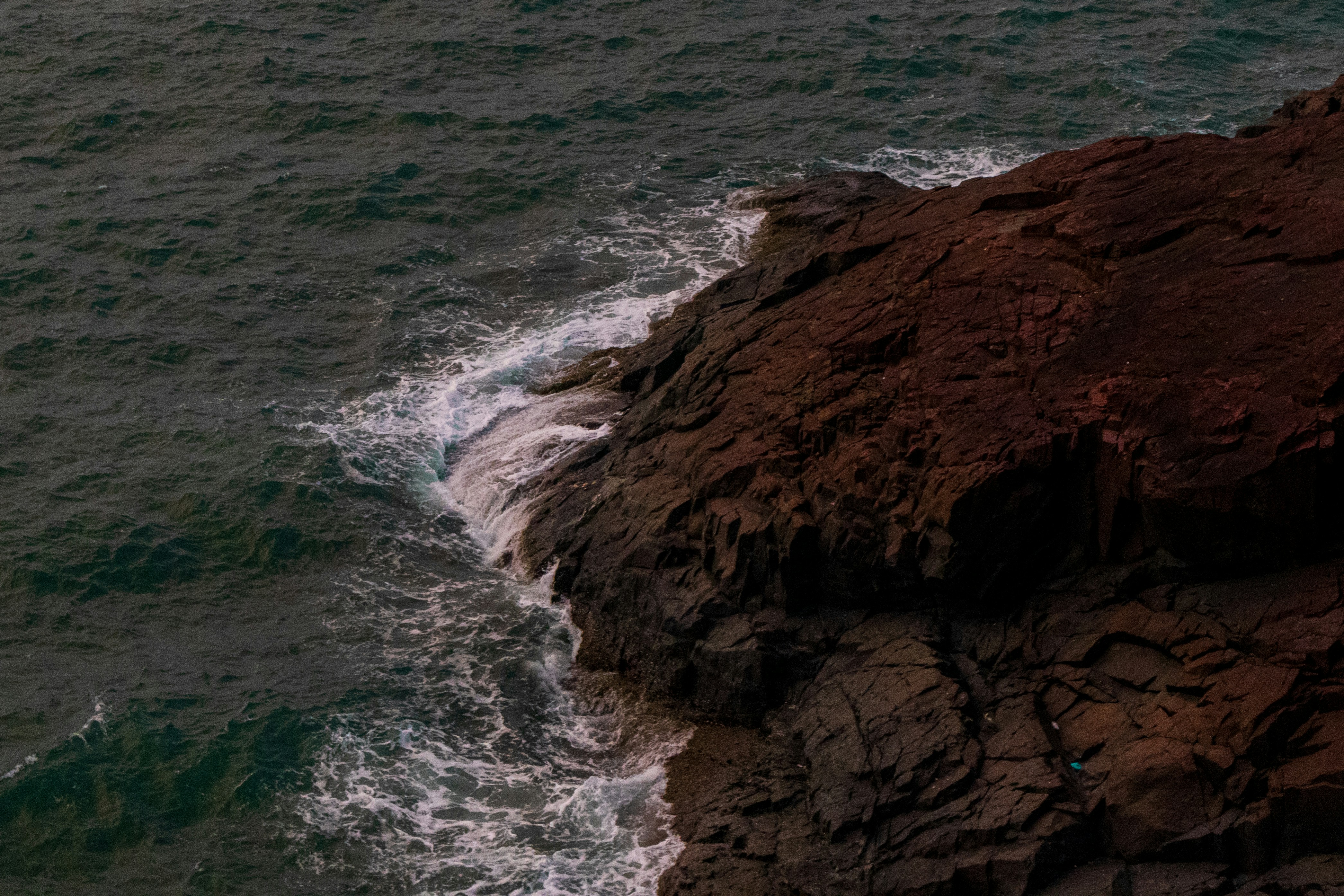 Rugged Red Cliffs Meet Turbulent Green-Gray Seas