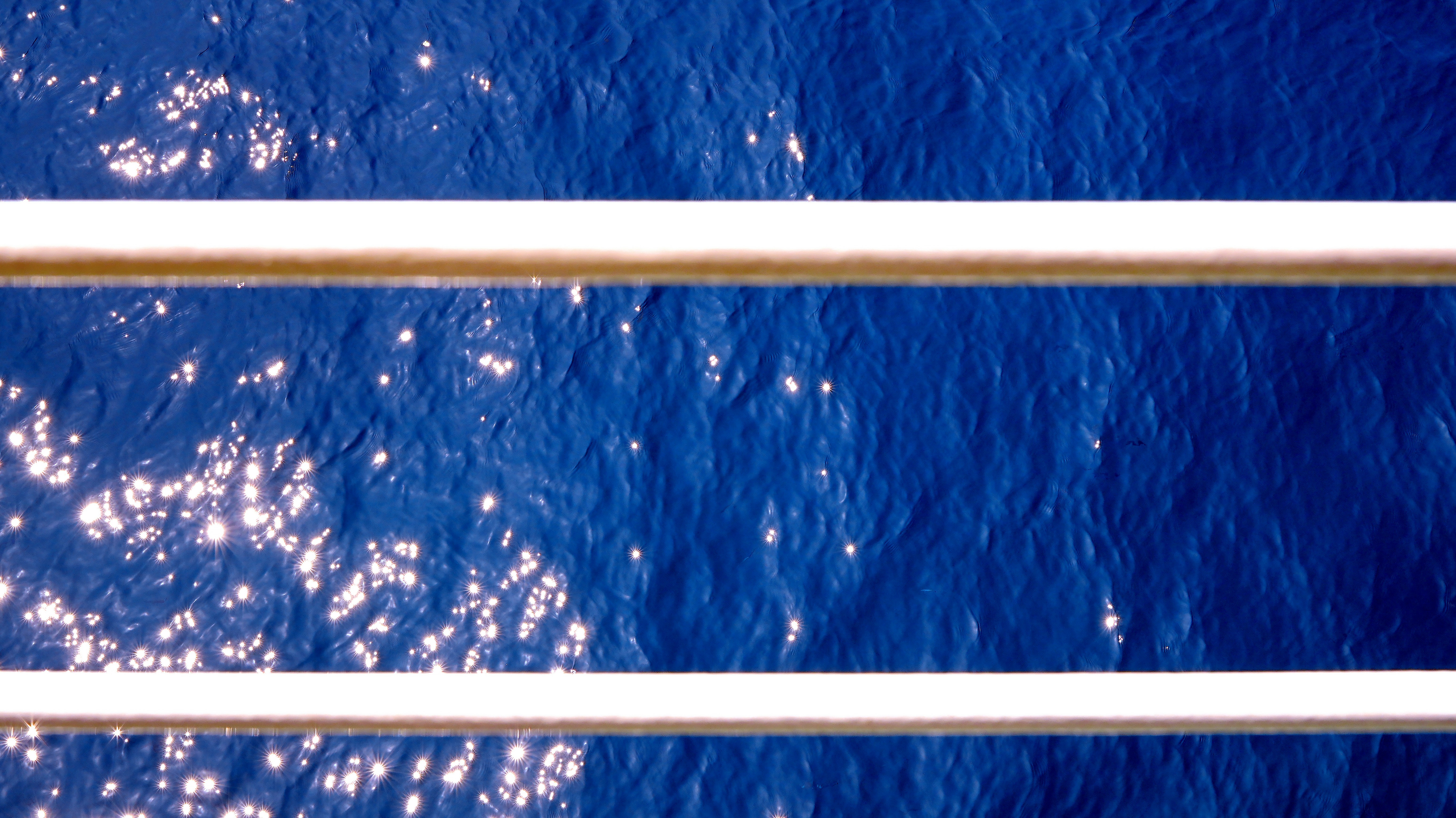 Sea Prism: Sunlight on Blue Currents Between Deck Slats