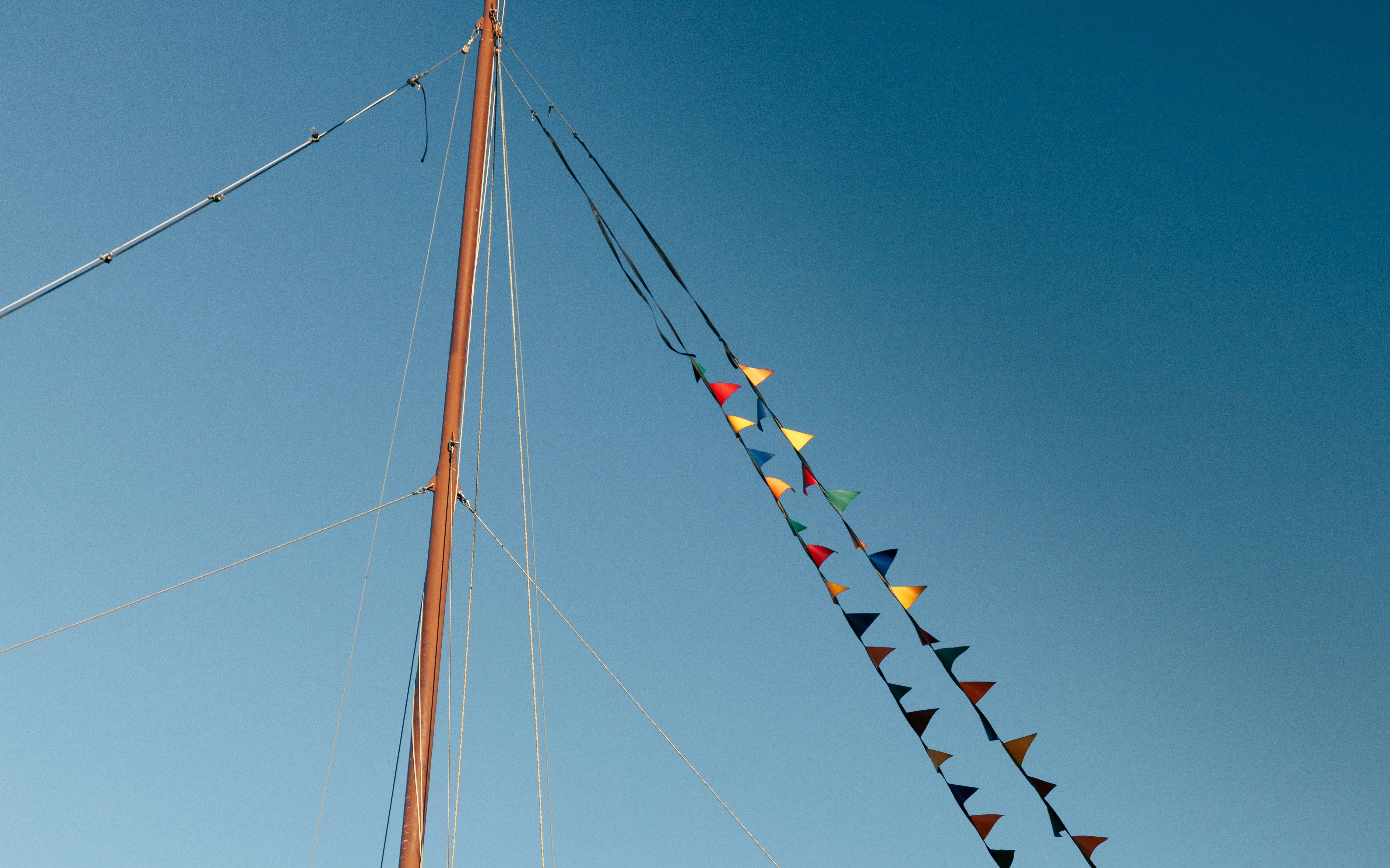 Flagged sailboat mast beneath a clear blue sky