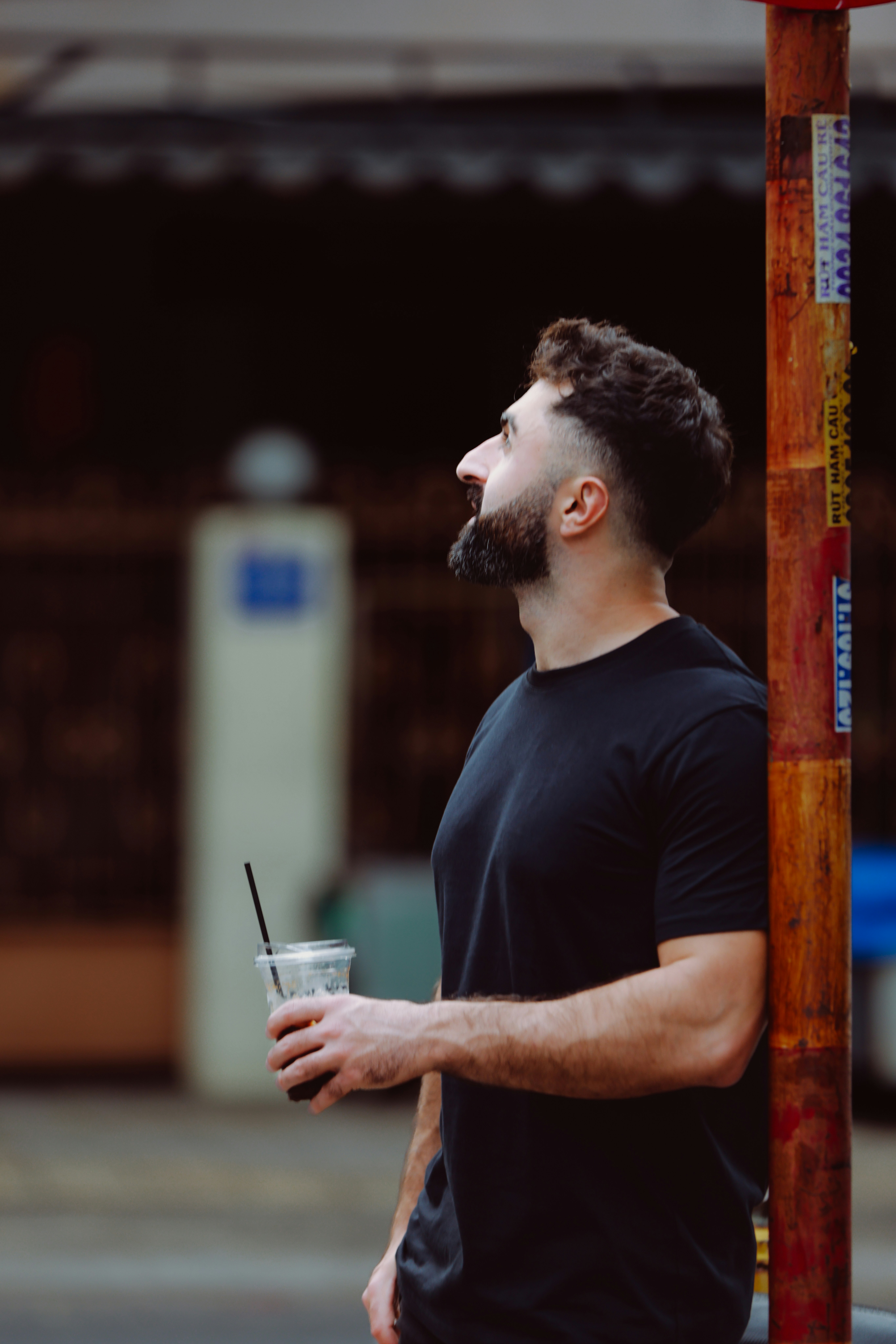 Profile at the Edge: A Man with a Drink Beneath a Rusted Post