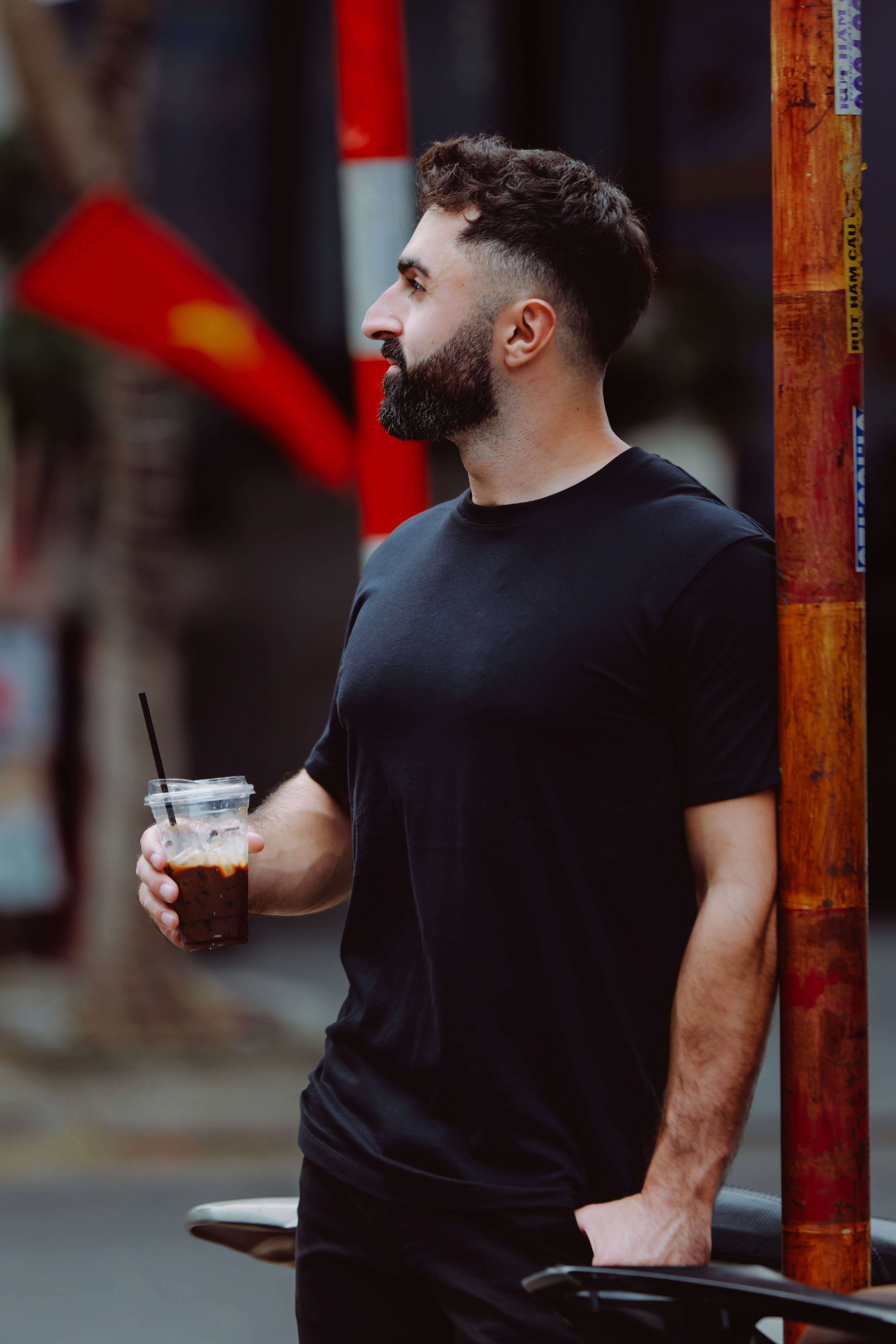 Bearded Stranger with Iced Coffee by a Rusty Pole
