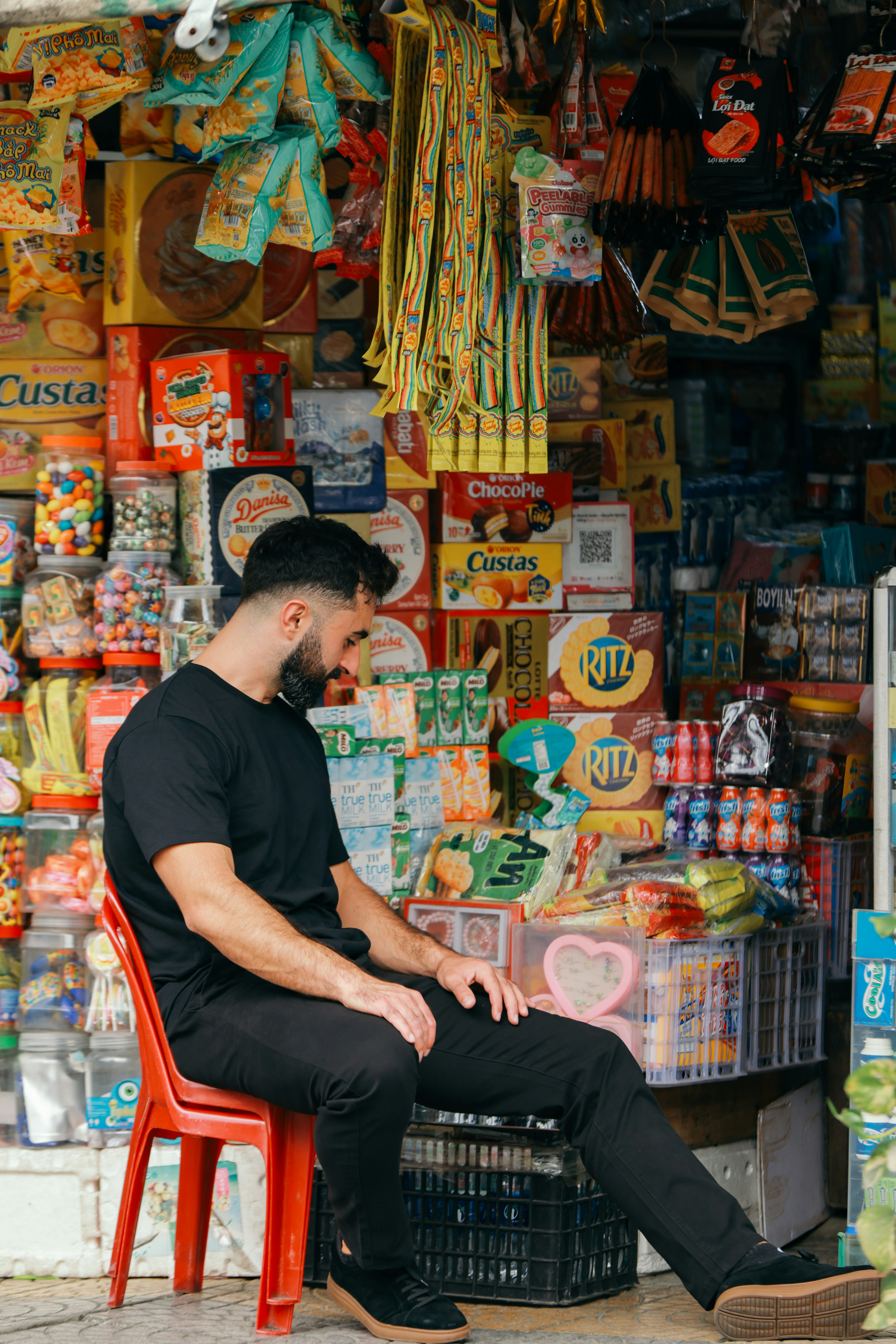 Portrait in a Colorful Stallscape: A Quiet Moment Among Candy and Snacks