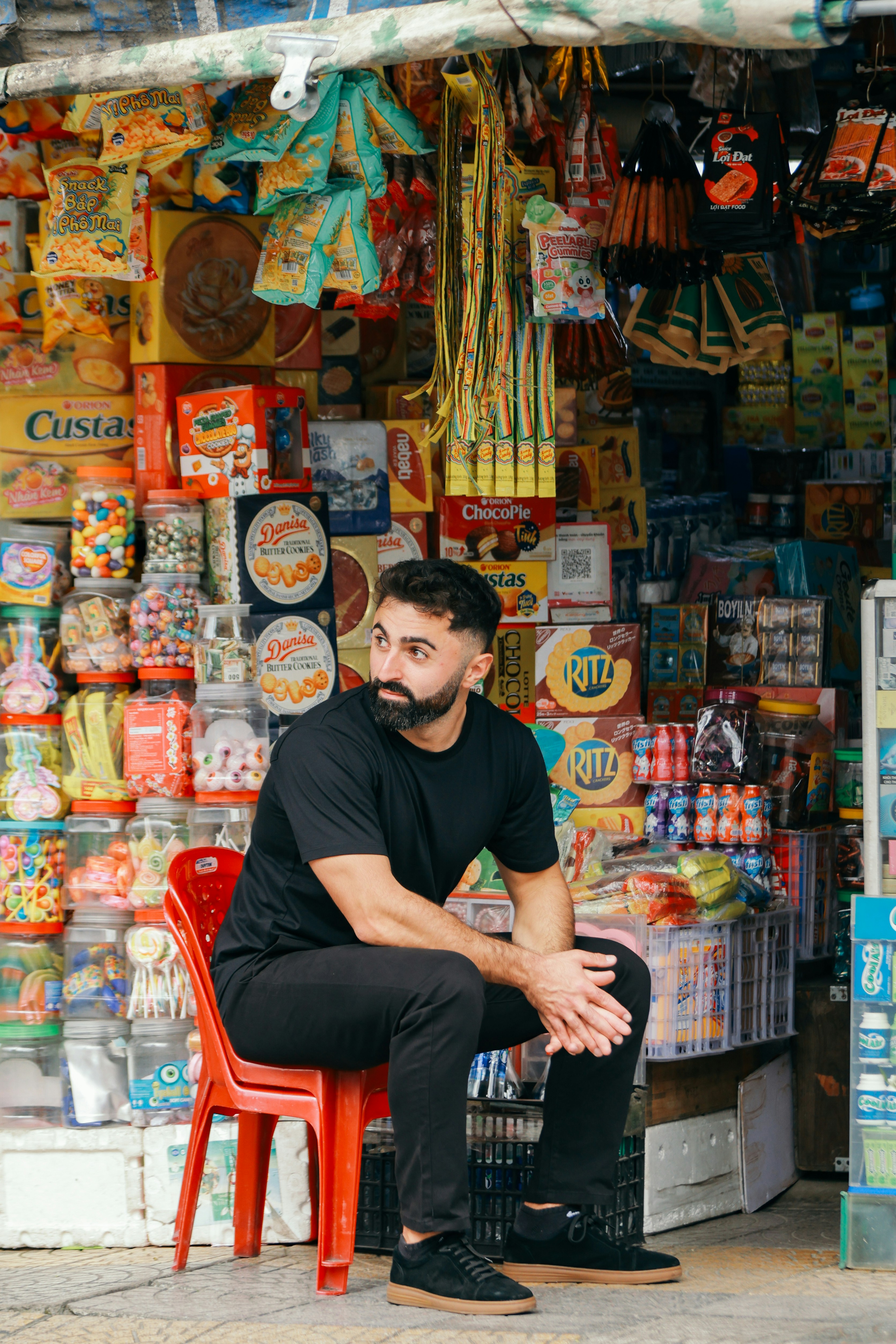 Street vendor portrait: a contemplative moment amid a colorful shop facade