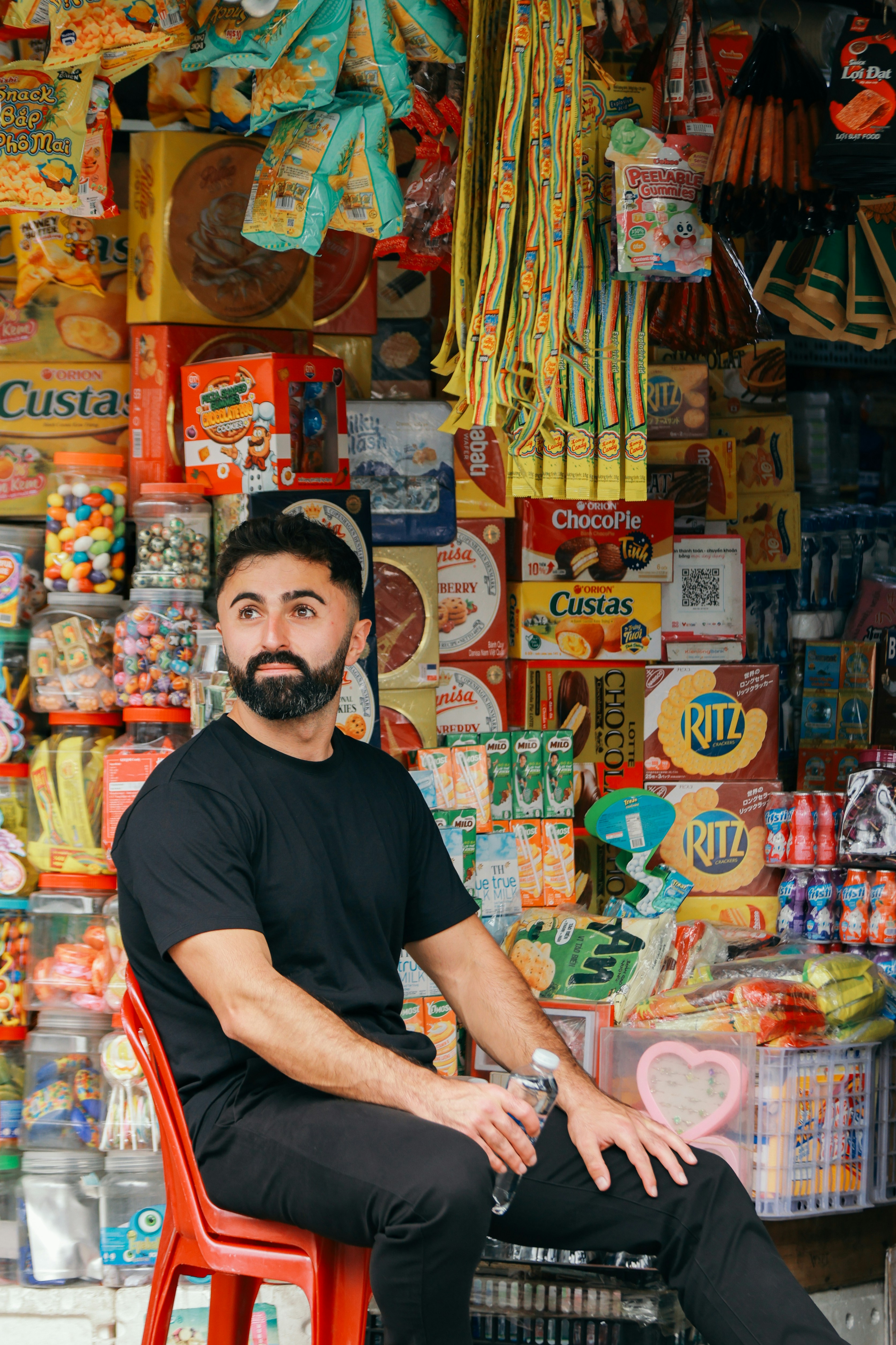Man in a Black Shirt at a Colorful Market Stall