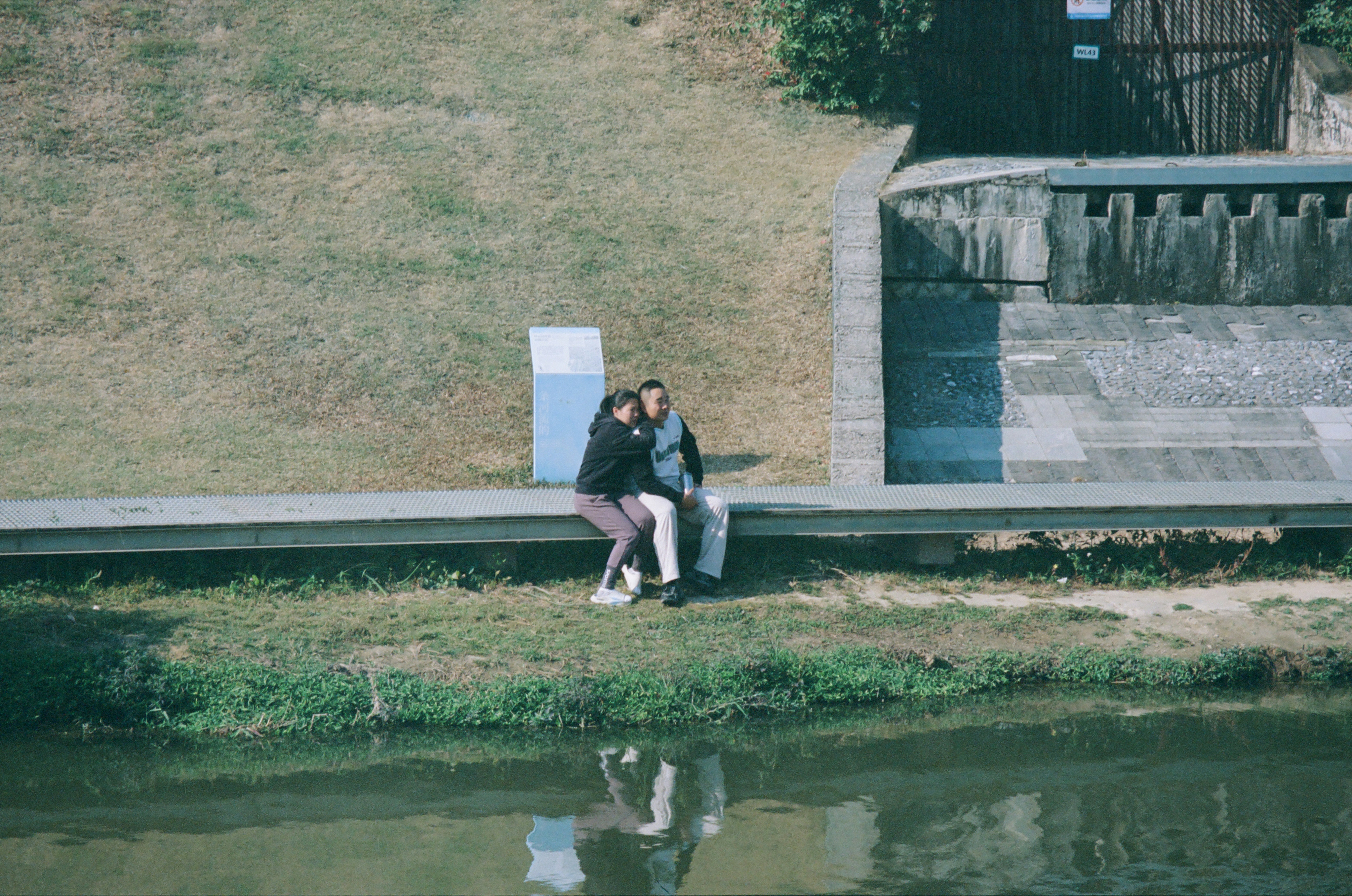 Two Friends Shelter on a Riverside Bench