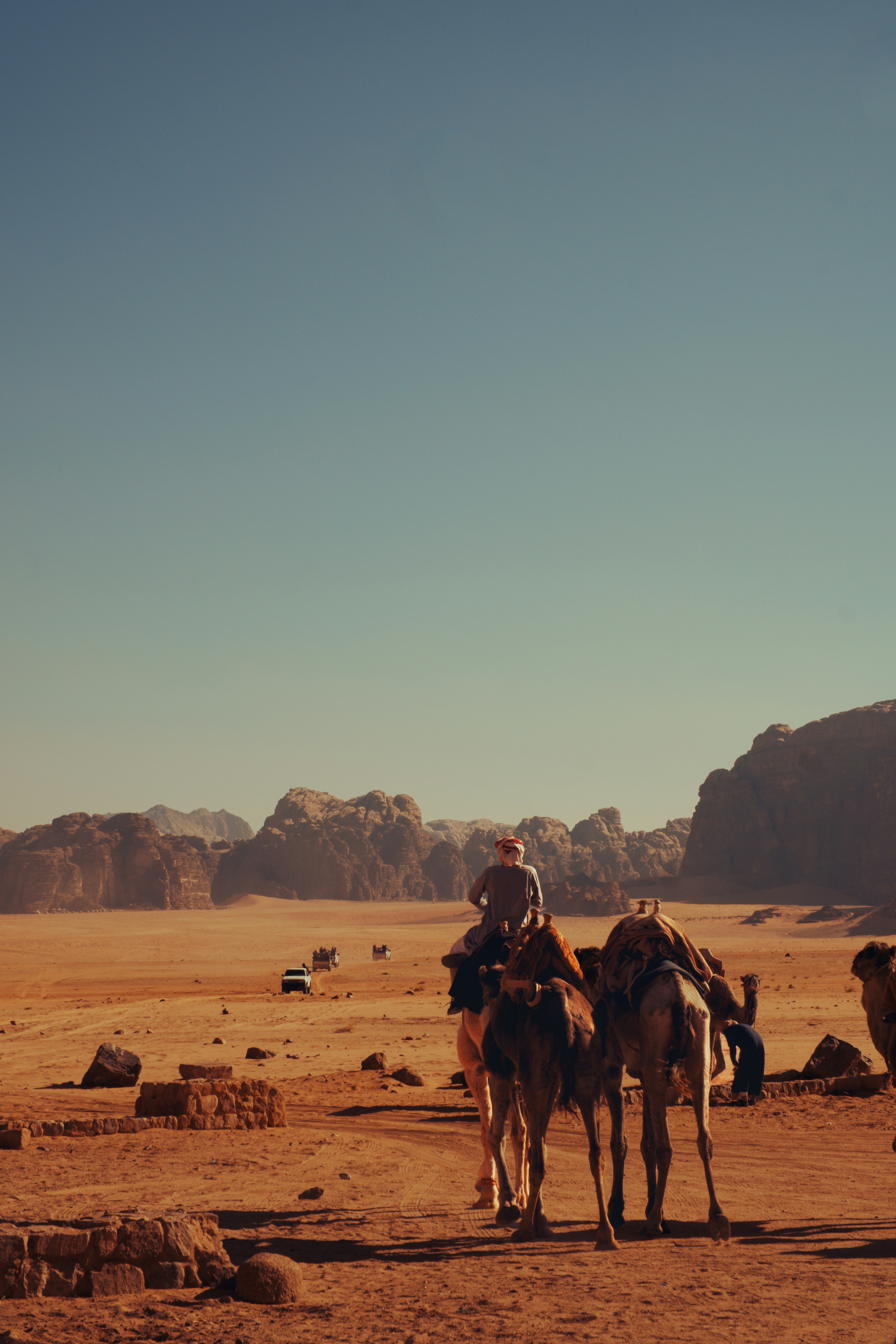 Dusty Caravan Ridge: Riders and Camels Walk the Red Desert