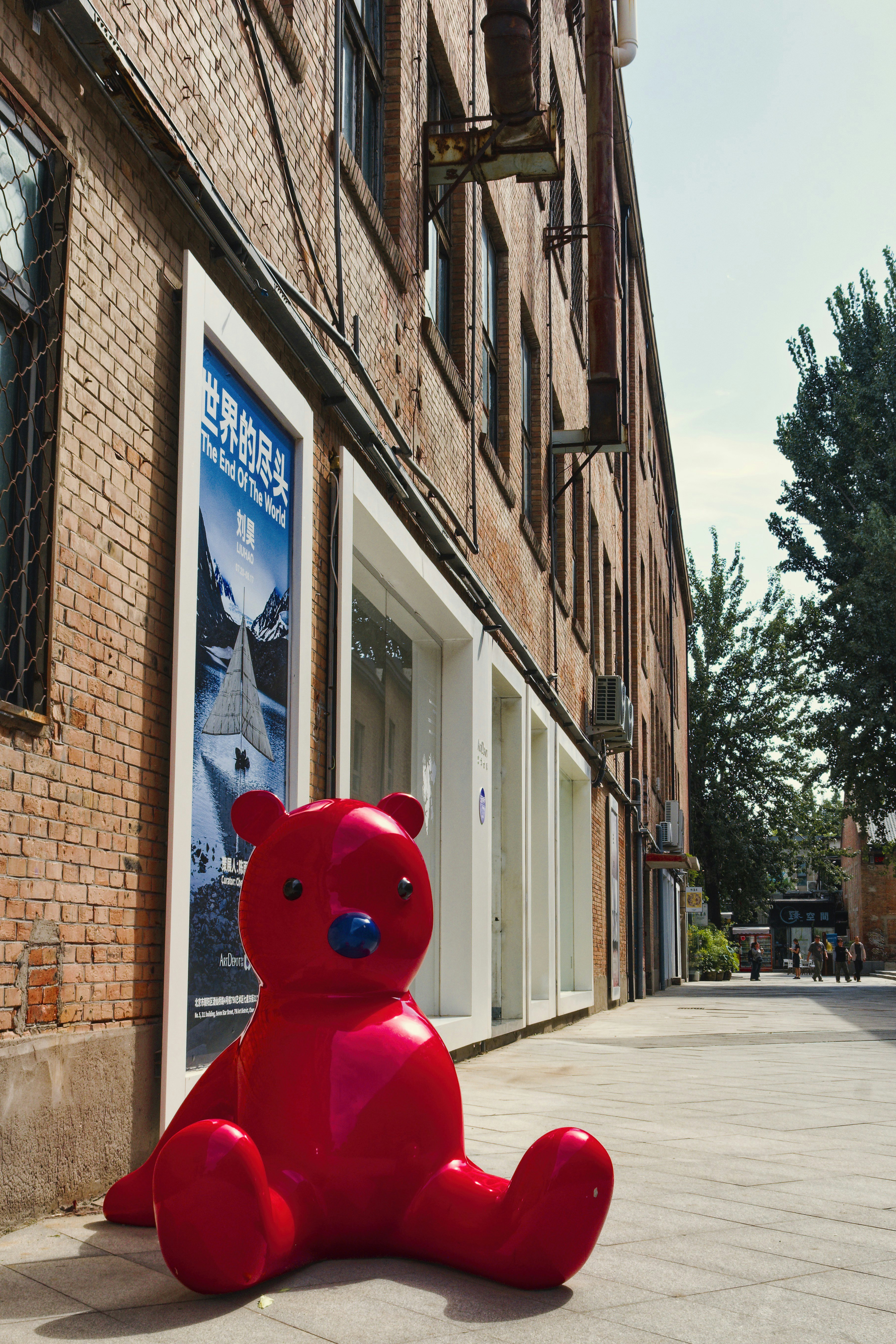 Red Toy Sentinel Anchored on a Sunlit City Walk
