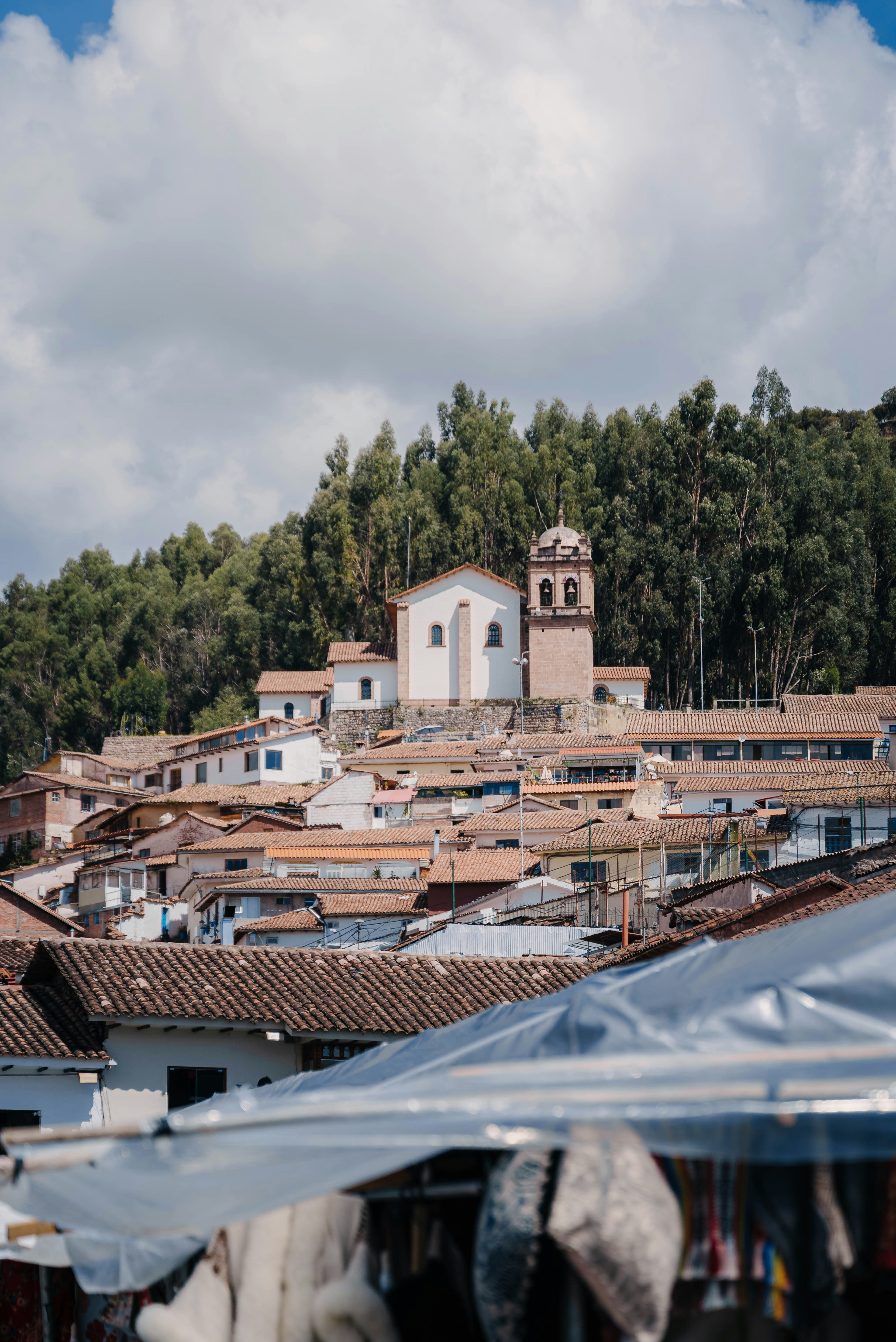 White chapel atop terracotta rooftops under a forested hillside