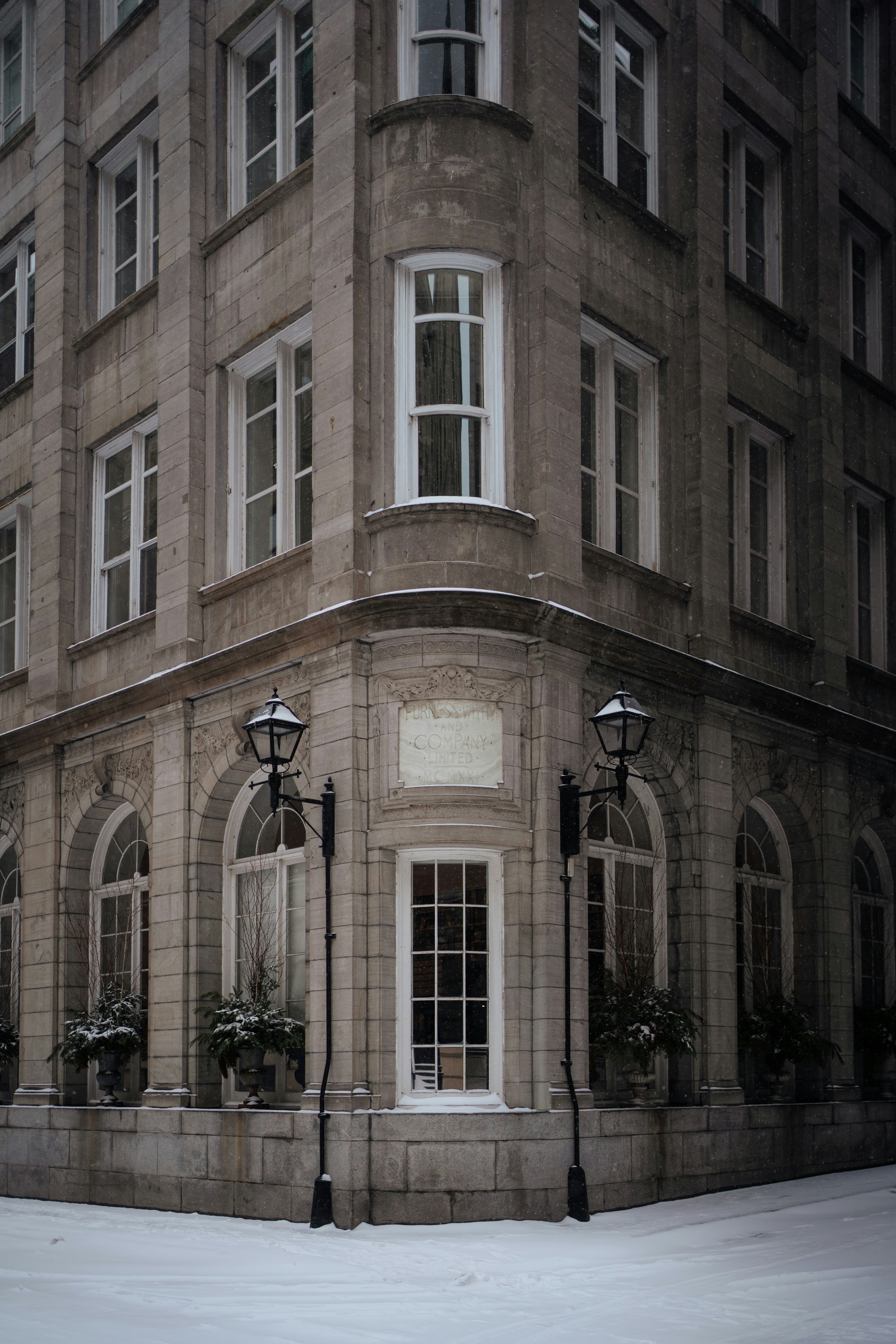 Cornerstone of Snow: Antique Stone Facade at a Quiet City Bend