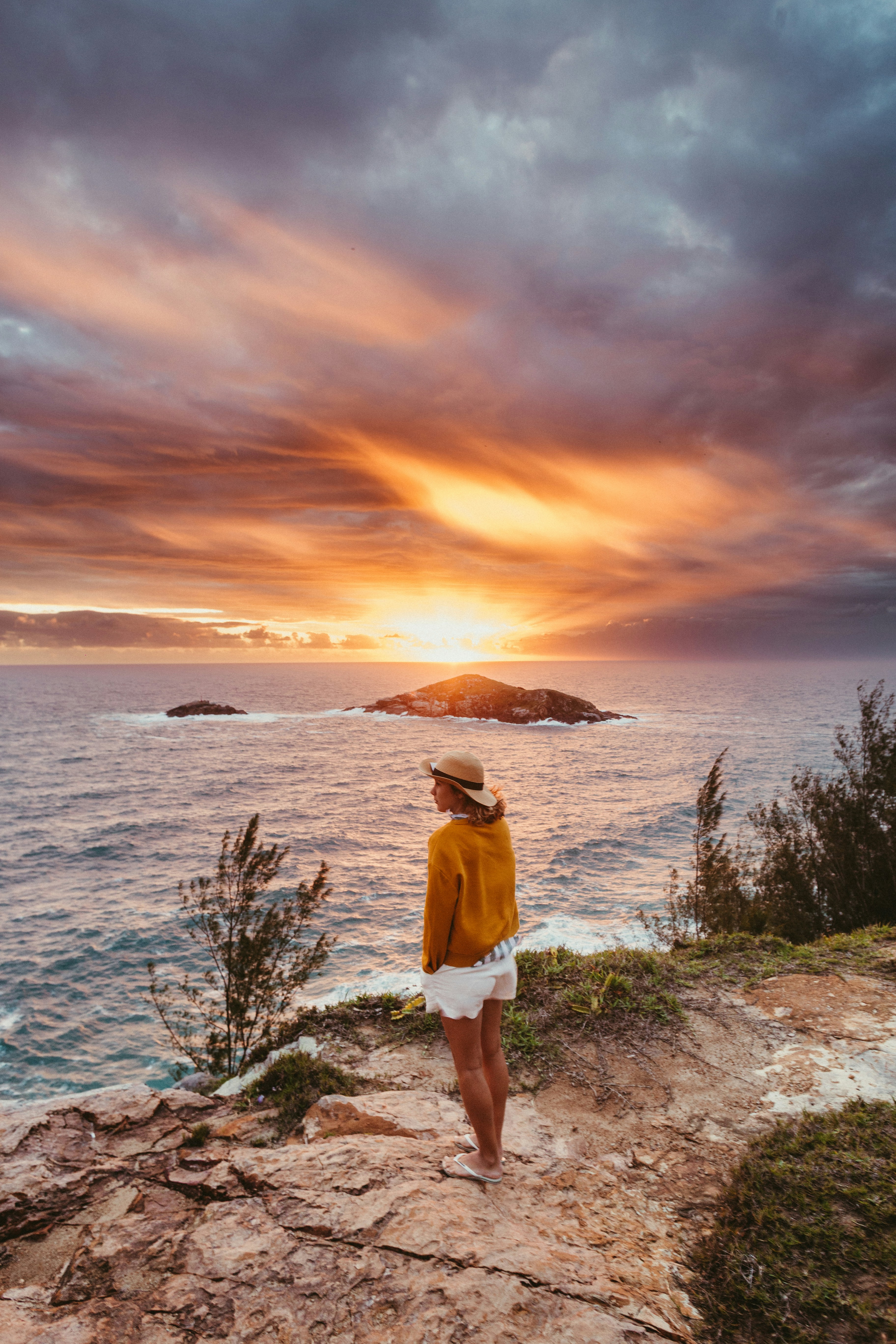 On the Edge of Light: A Woman in Citrus on a Cliff at Sunset