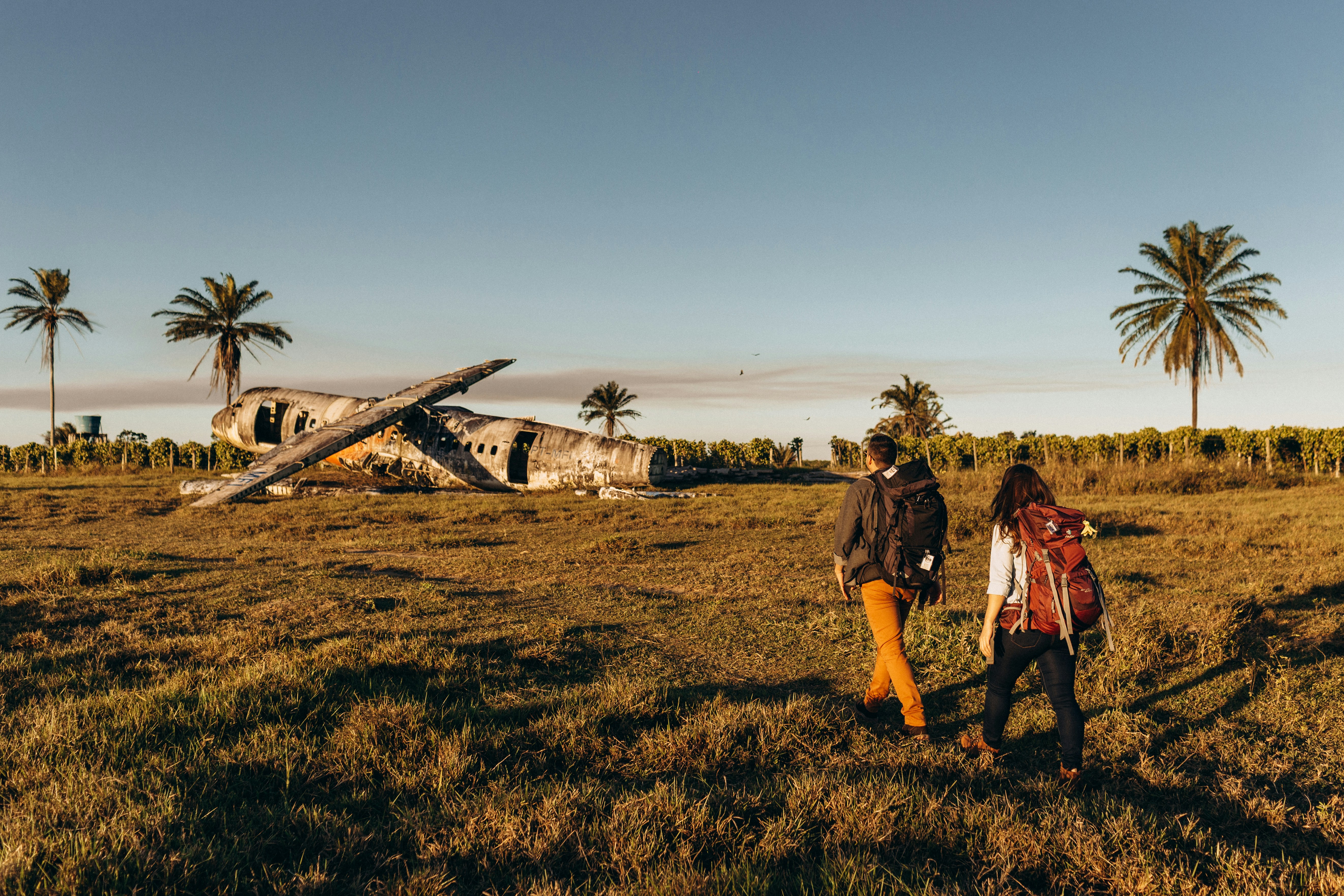 Two wanderers Approach a Sunlit Wrecked Aircraft on a Prairie