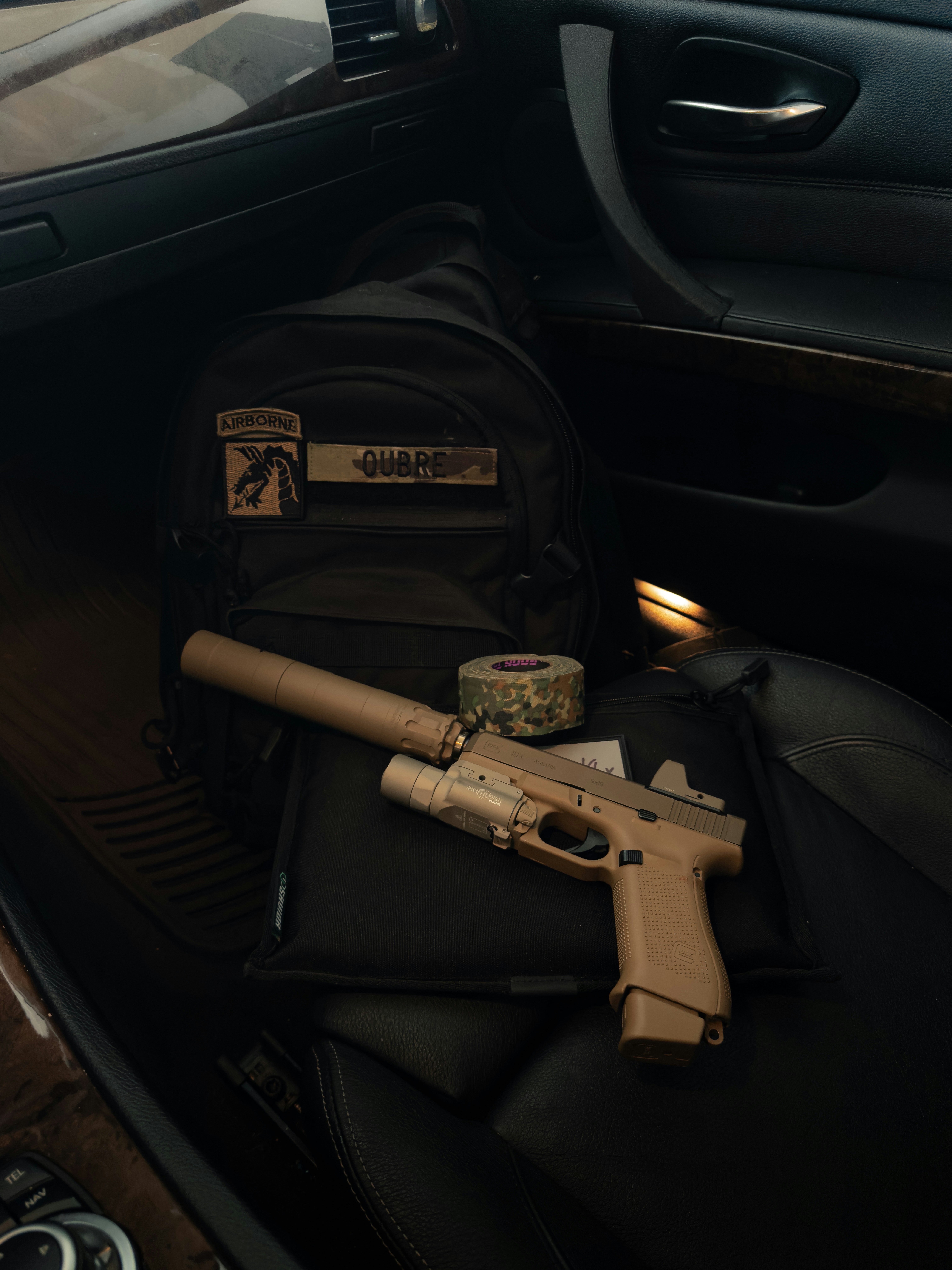 Tactical Gear in a Car Cabin: Tan Pistol on a Backpack