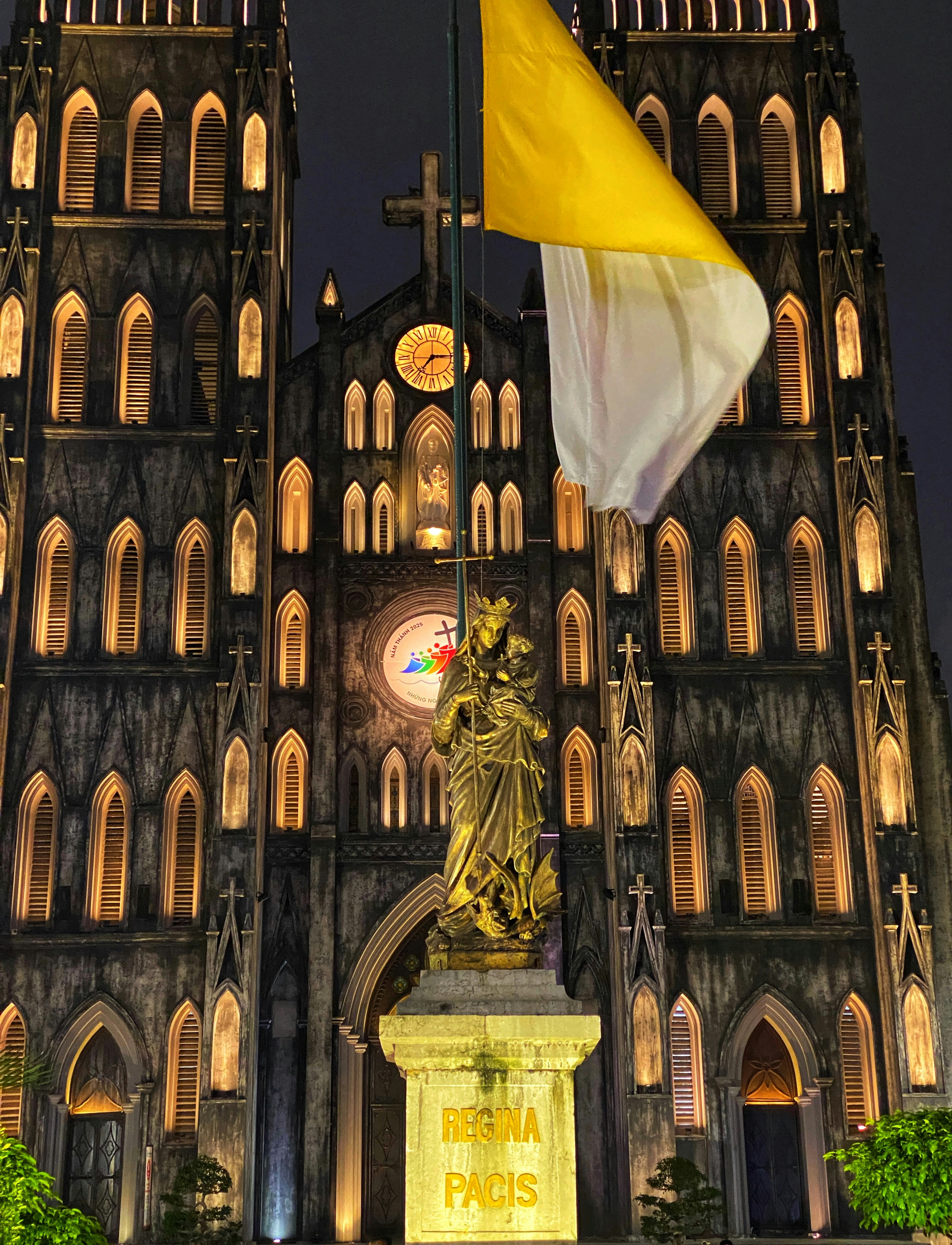 Flag and statue glow before Notre-Dame Cathedral at night