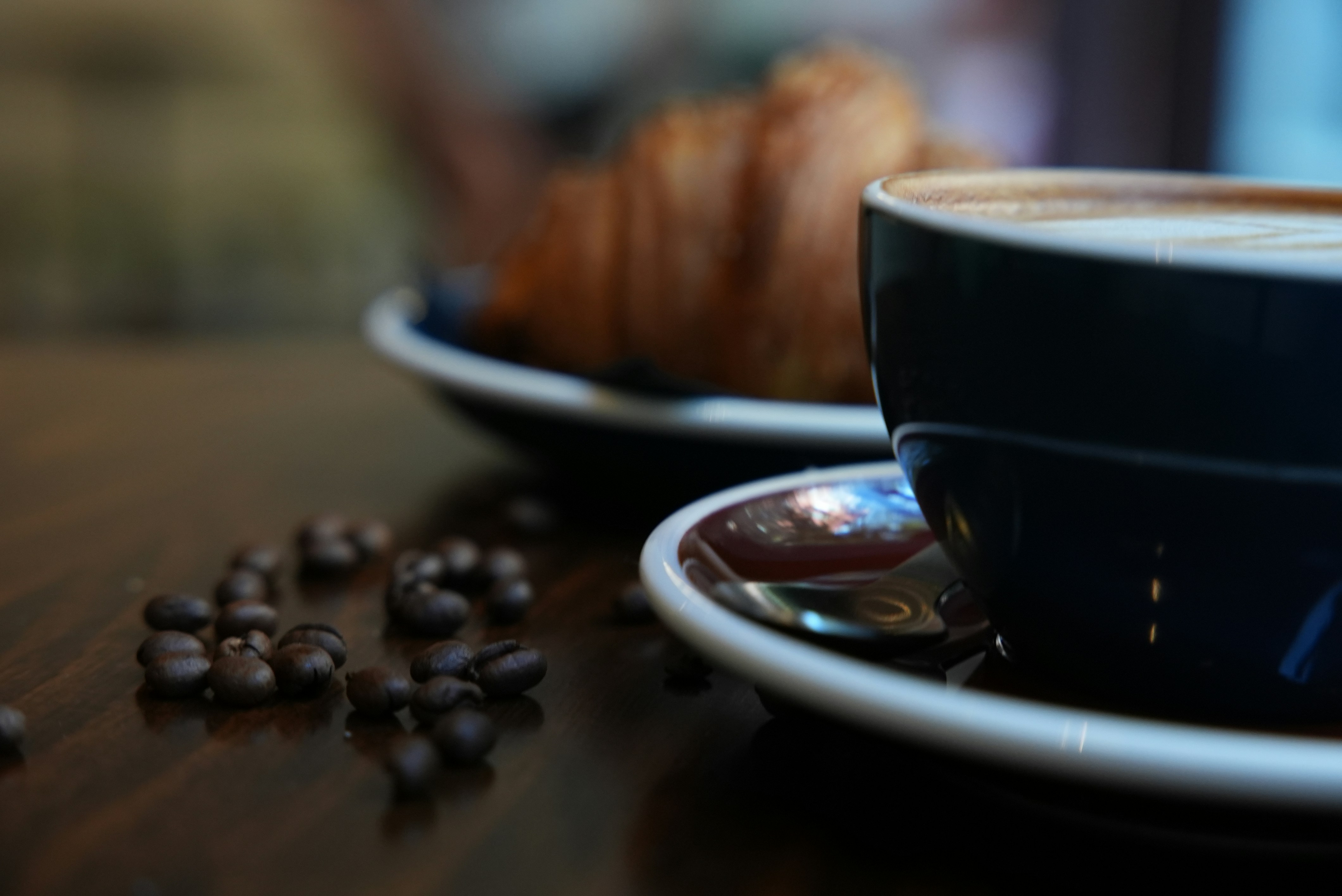 Quiet Espresso Moment: Cup in Focus with Pastry Blur