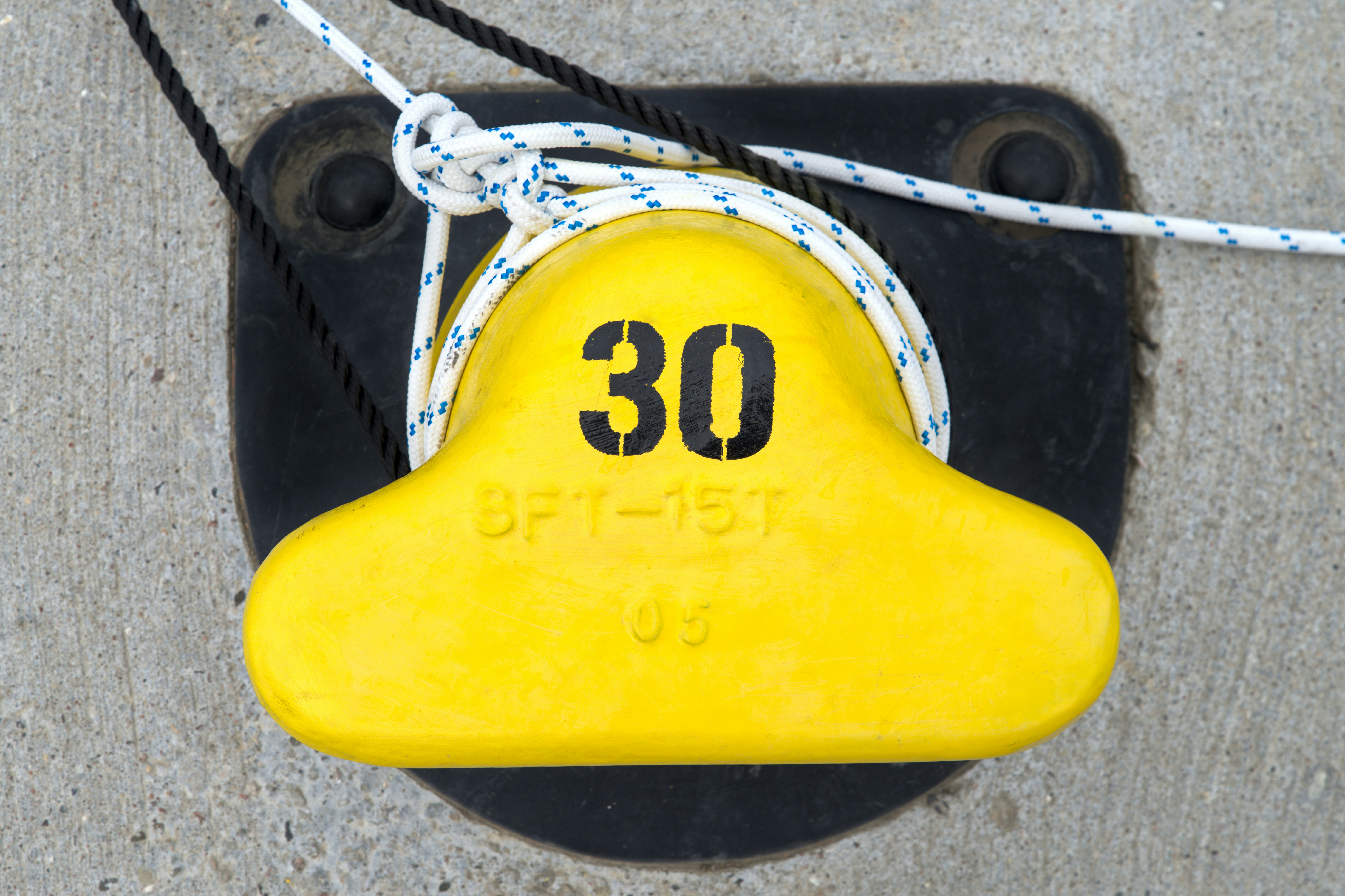 Yellow mooring buoy with braided rope on a concrete surface